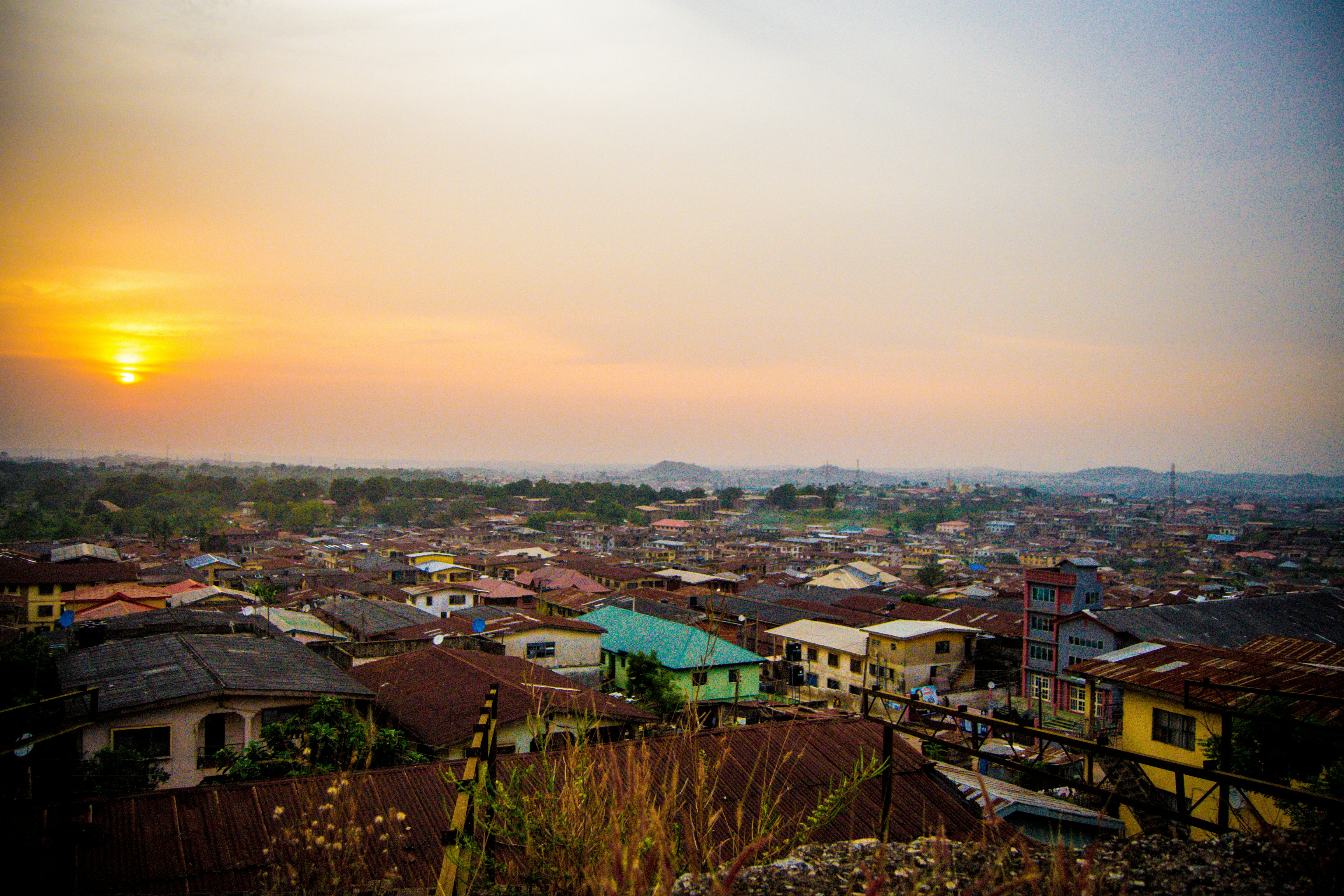 Rooftops stretch beneath a vibrant sunset sky, with the sun dipping near the horizon.