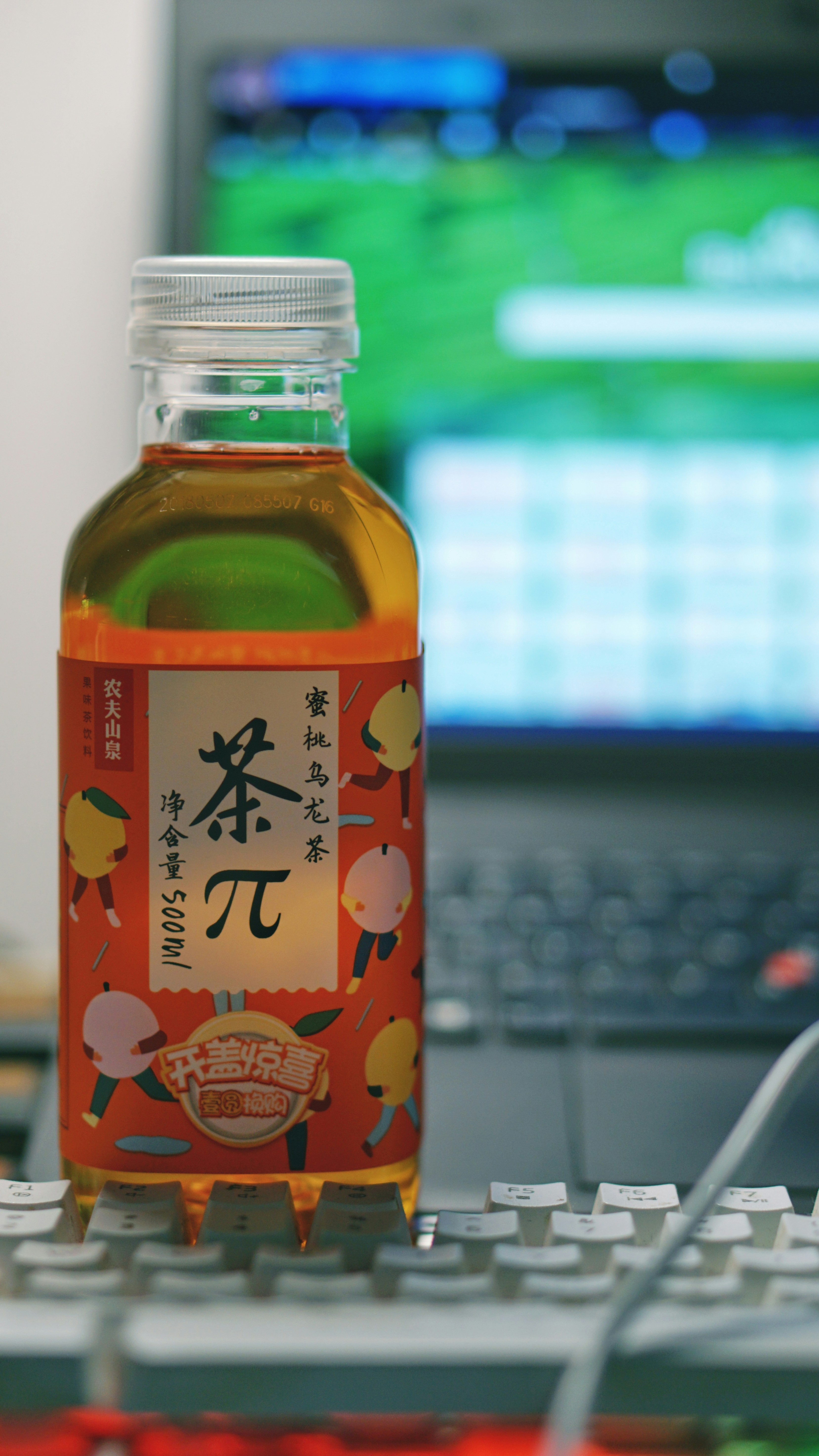 Amber Tea Bottle Anchors a Quiet Desk Scene Against a Neon Laptop Glow