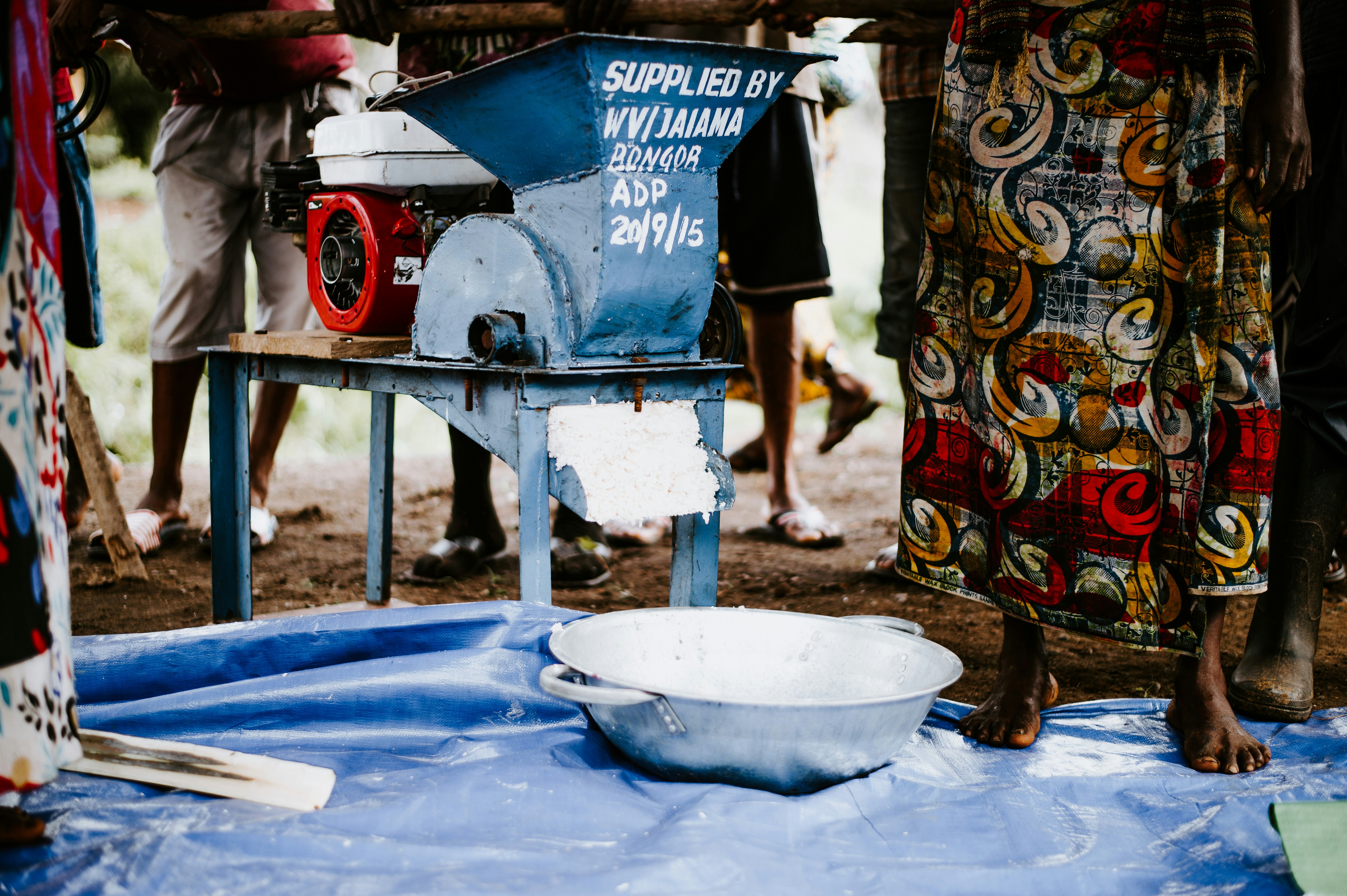Mechanical mill and market scene: blue seed grinder at center
