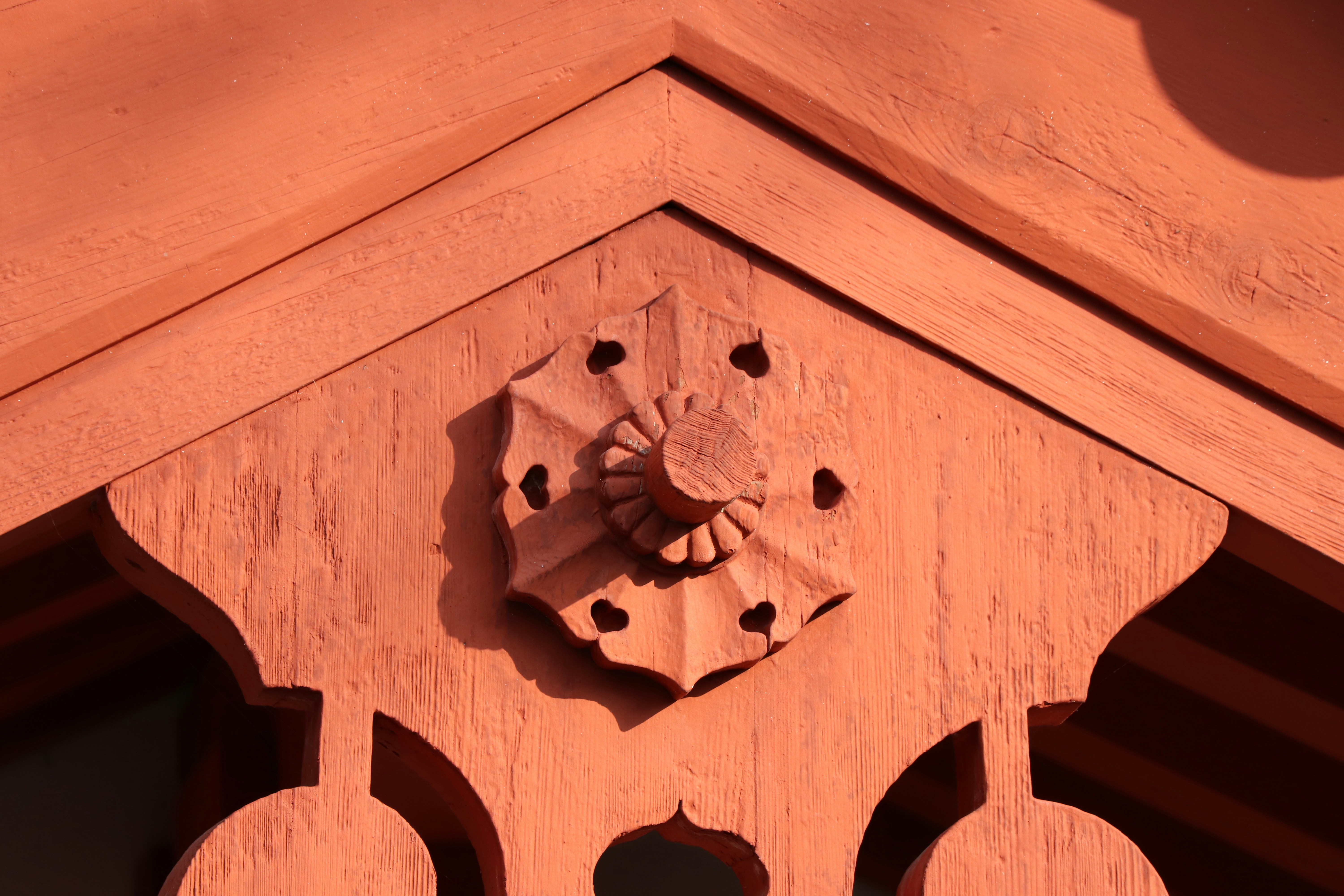 Sunlit Timber Crest: a Carved Floral Emblem on an Eave