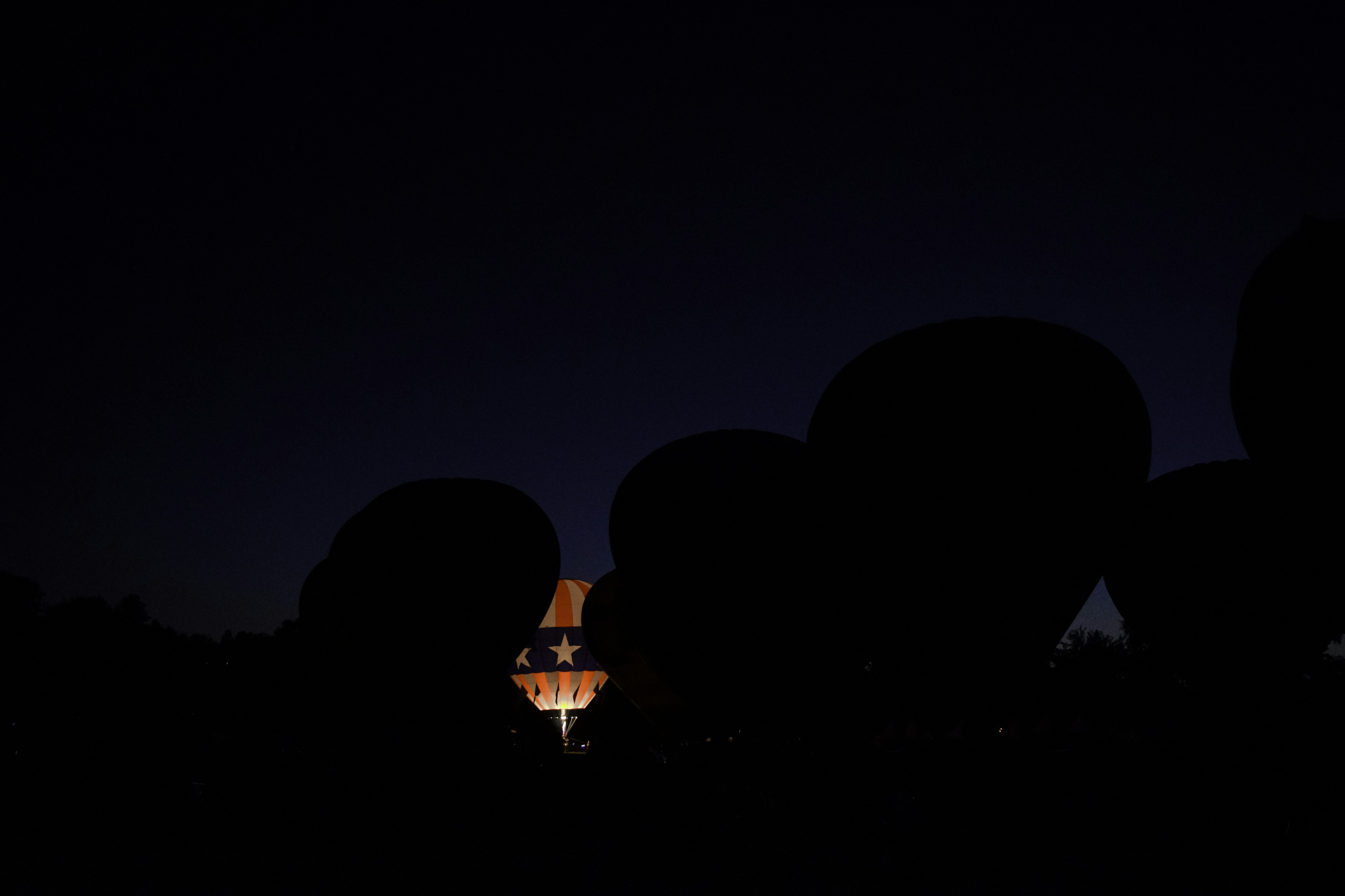 Beacon Amid Balloon Silhouettes at Dusk