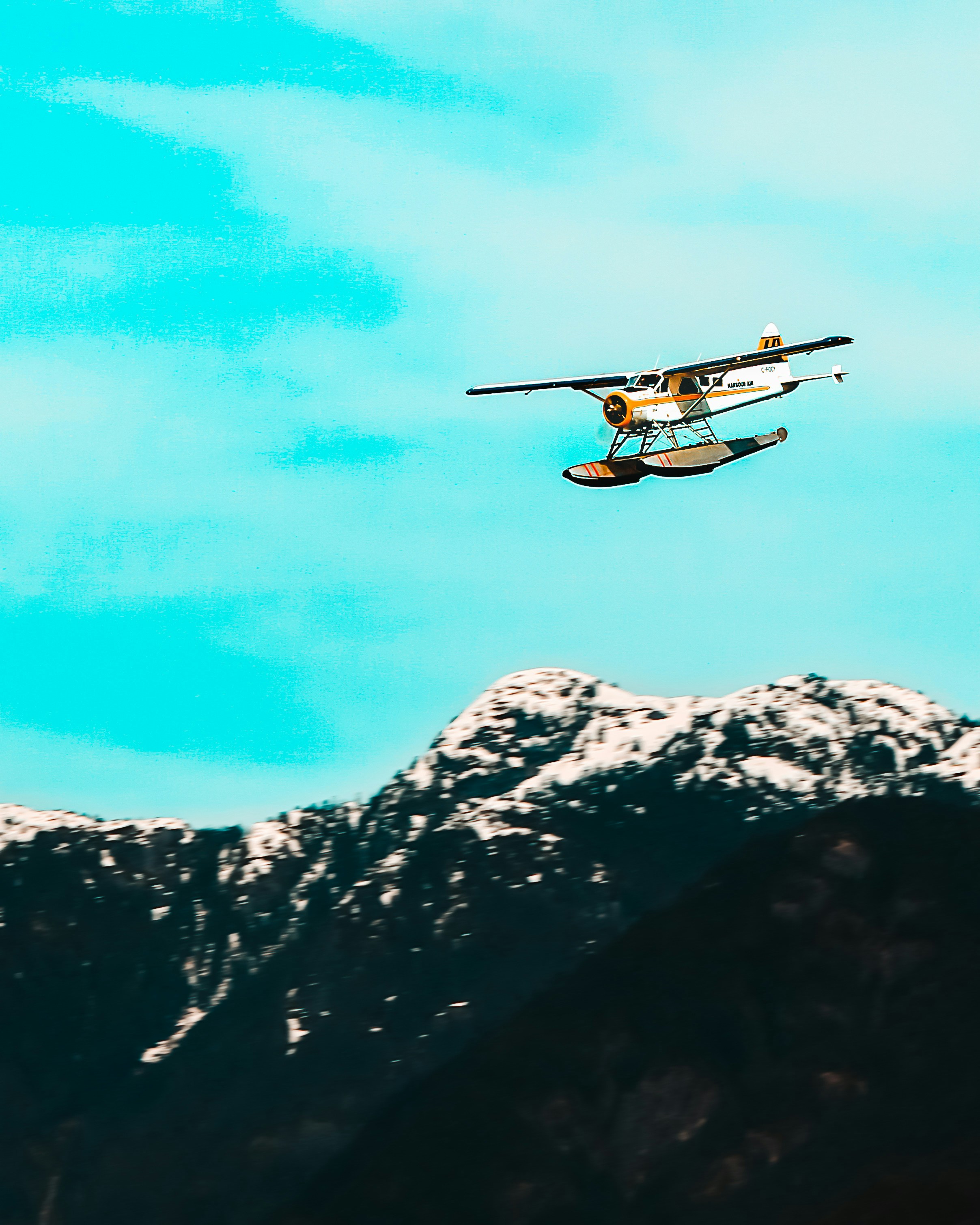 Floatplane skims a cerulean expanse above snow-dusted peaks