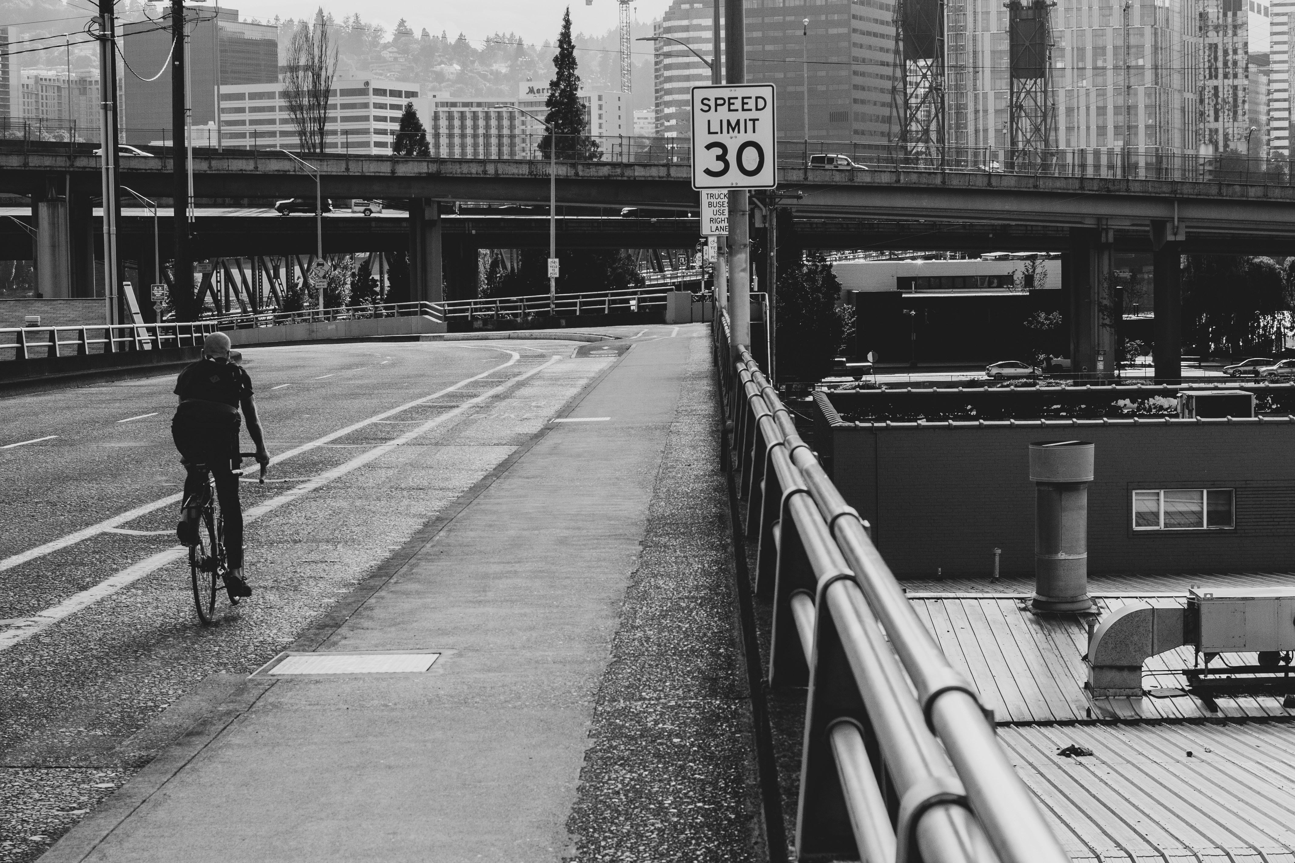 Cyclist traversing a bridge in a cityscape with skyscrapers in the background.