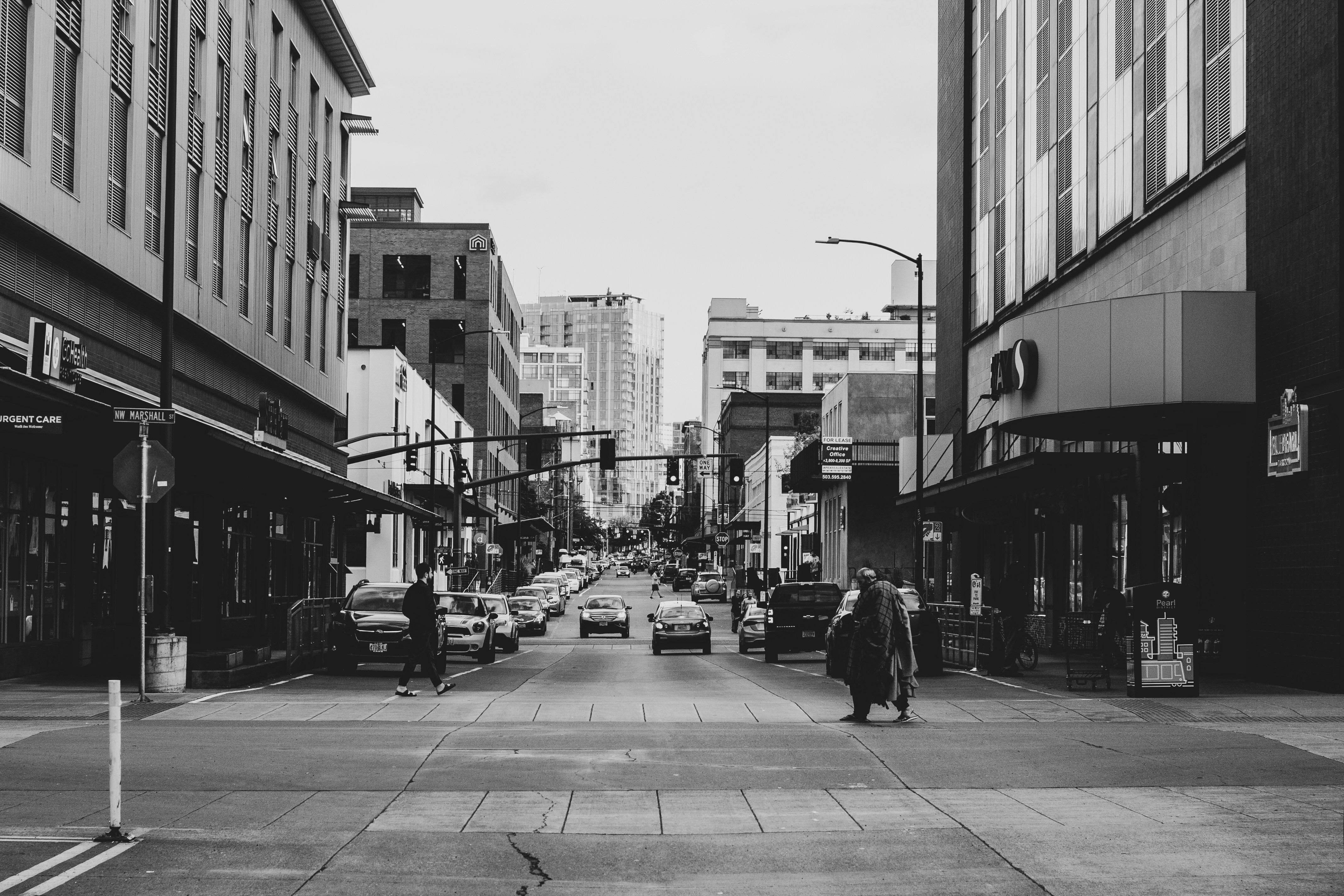 Black and white street scene capturing a bustling intersection lined with buildings and cars.