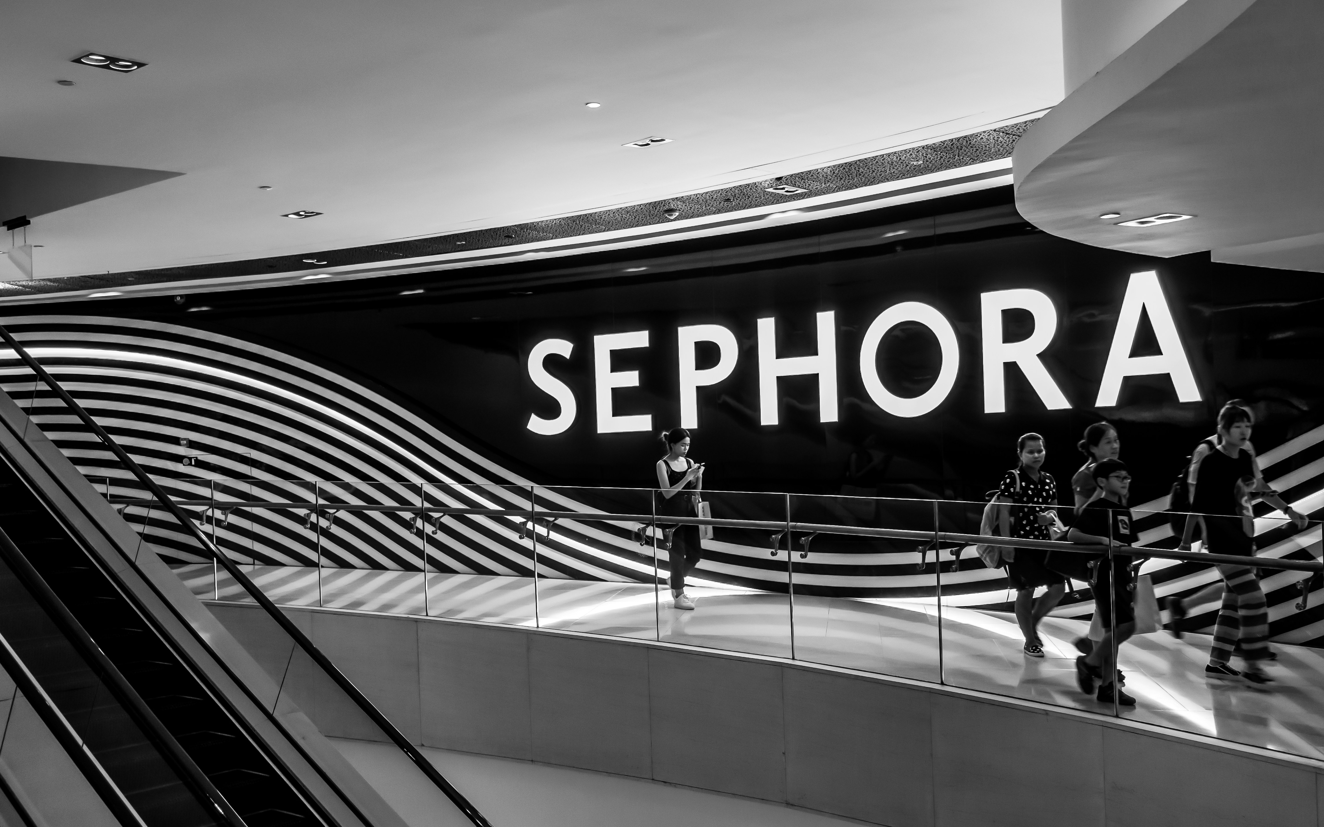 Grayscale photo of four women walking inside Sephora building photo ...