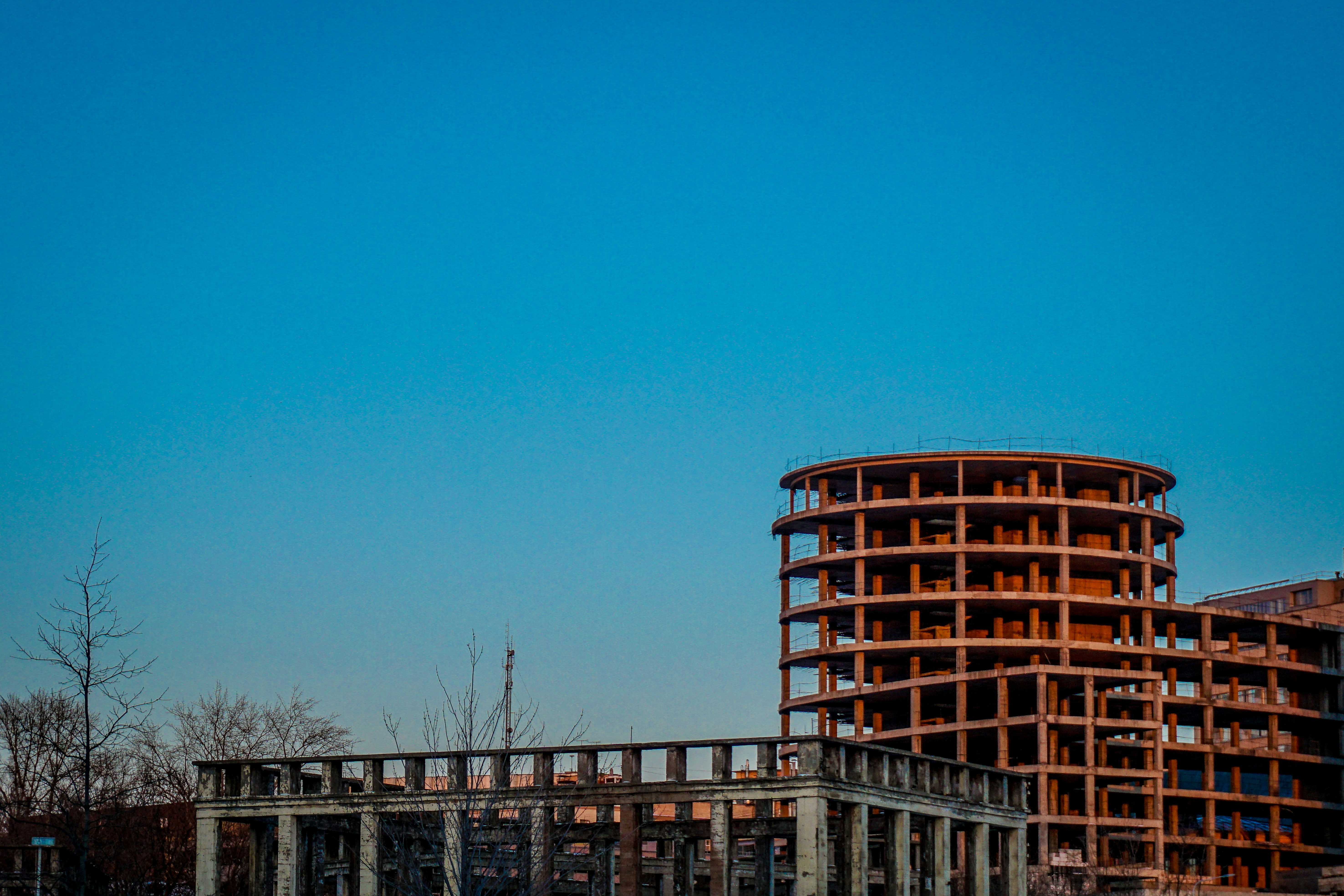 Rusted Skeleton: A Half-built Circular Tower Emerges Over an Industrial Frame