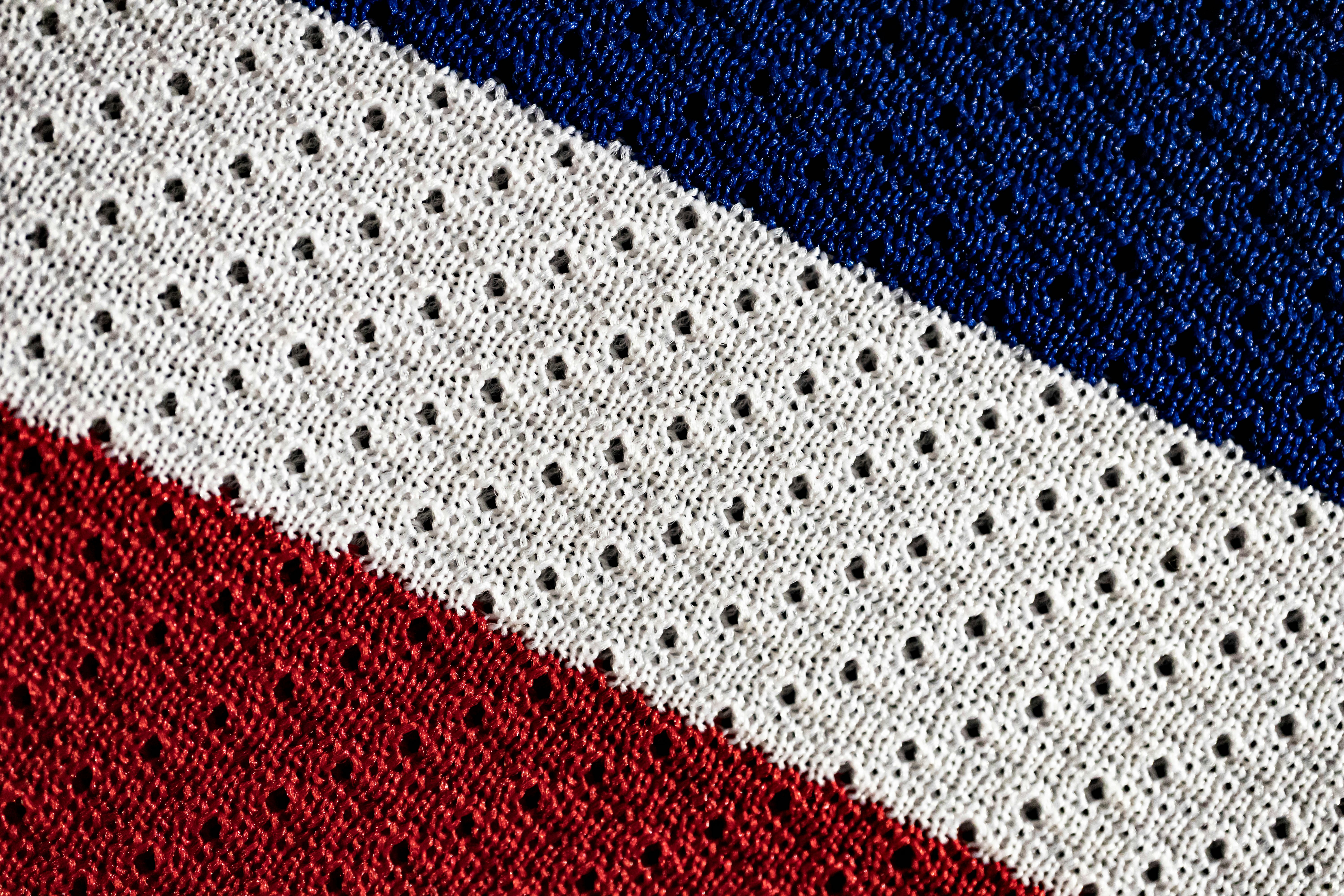 Close-up of a fabric featuring red, white, and blue stripes with perforated patterns, showcasing intricate textile design.
