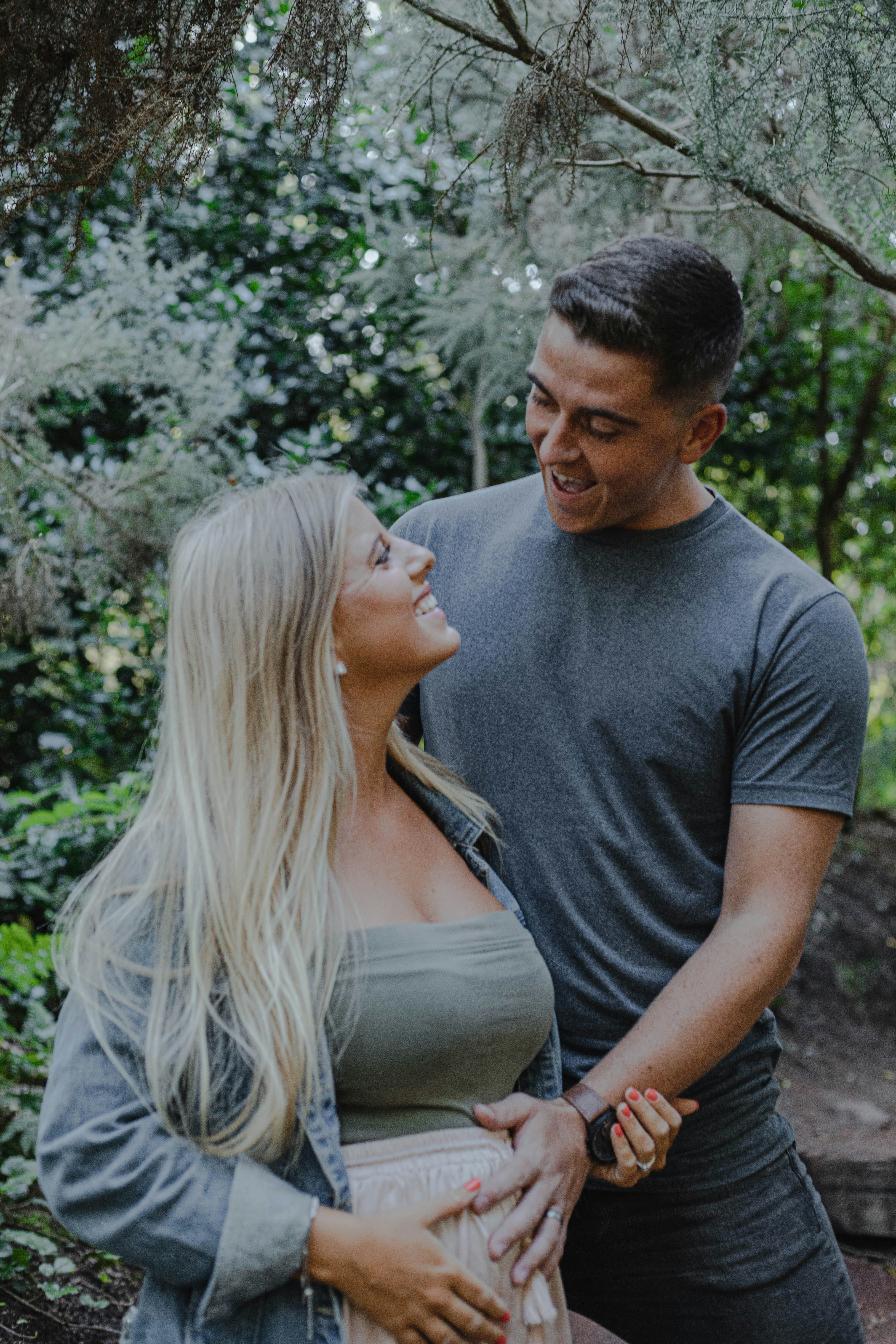 Dappled Light Embrace: An Expectant Couple's Joy in the Garden