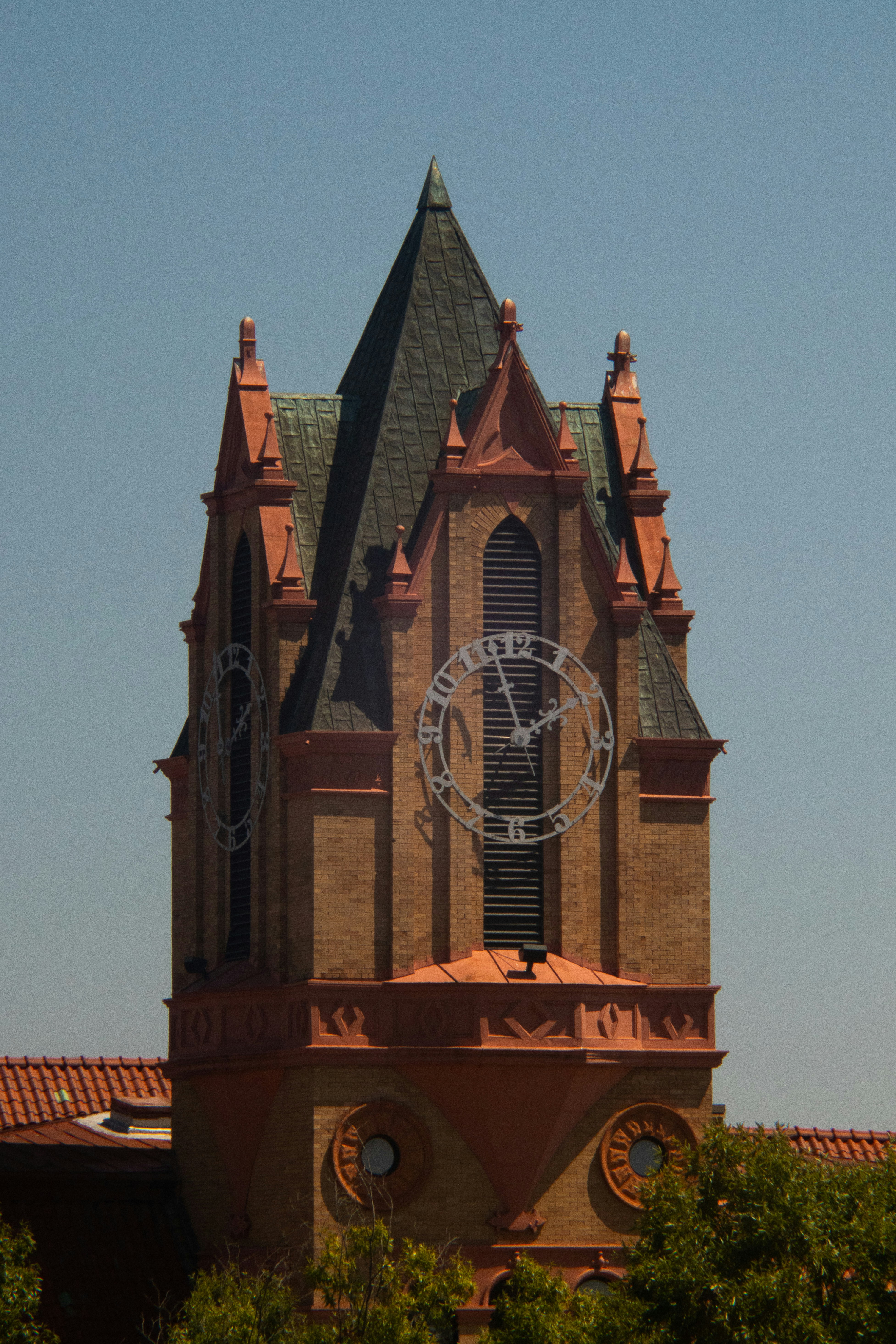 Historic clock tower with intricate architectural details and dual clock faces against a clear blue sky.