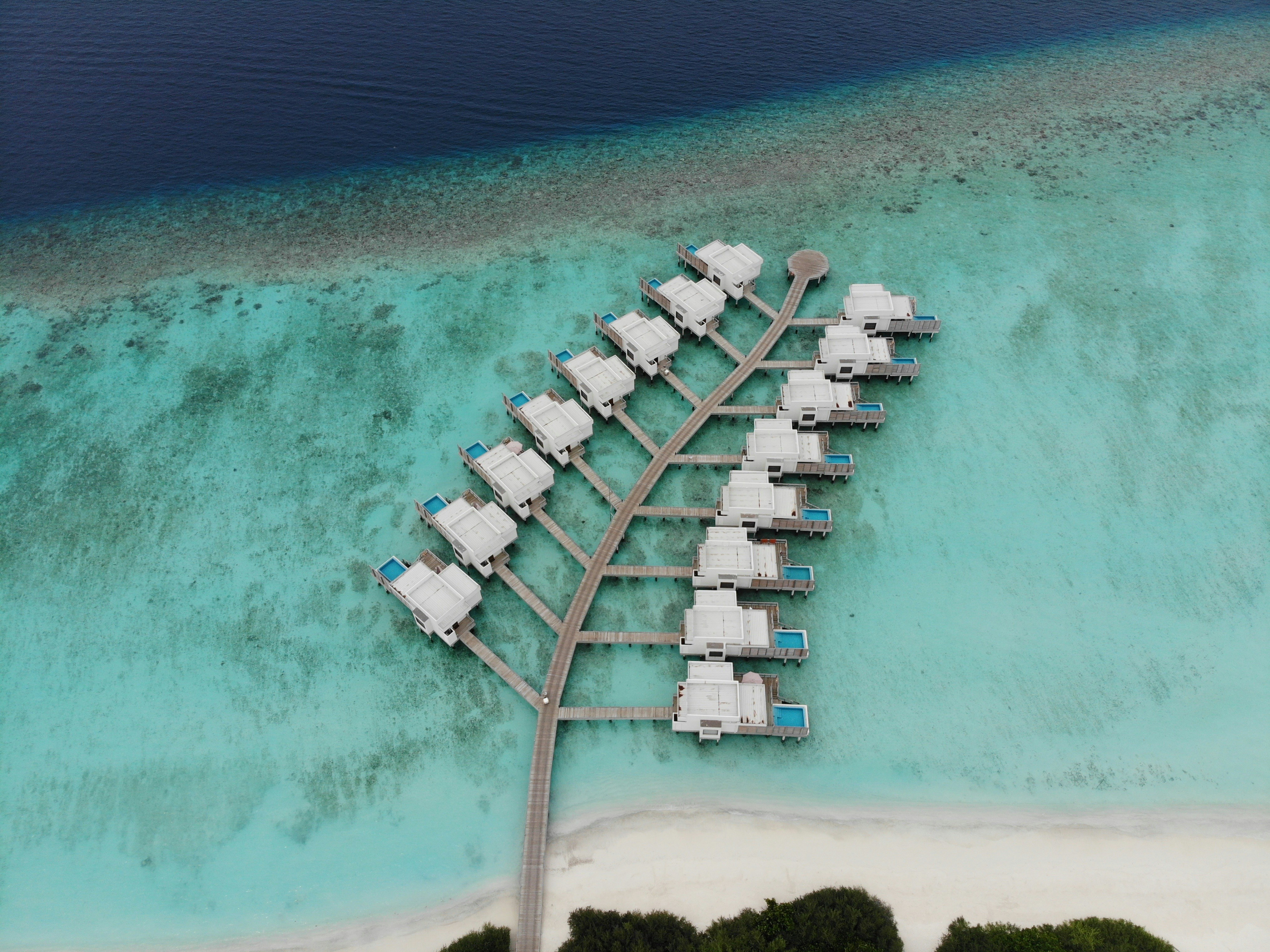 Luxury overwater villas arranged in a graceful curve above vibrant turquoise waters, showcasing an idyllic tropical setting.