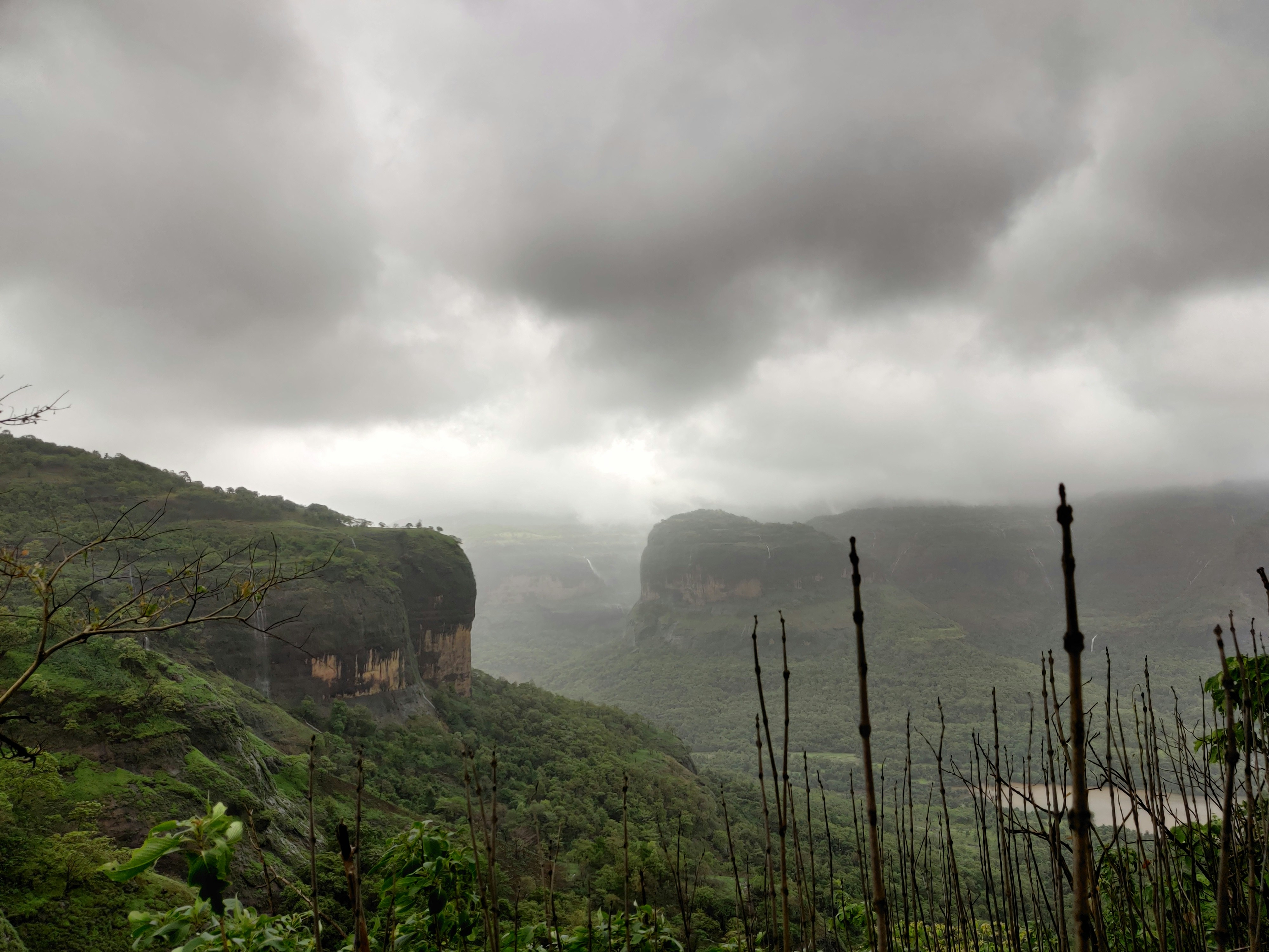Lush green valleys under a blanket of dark, looming clouds.