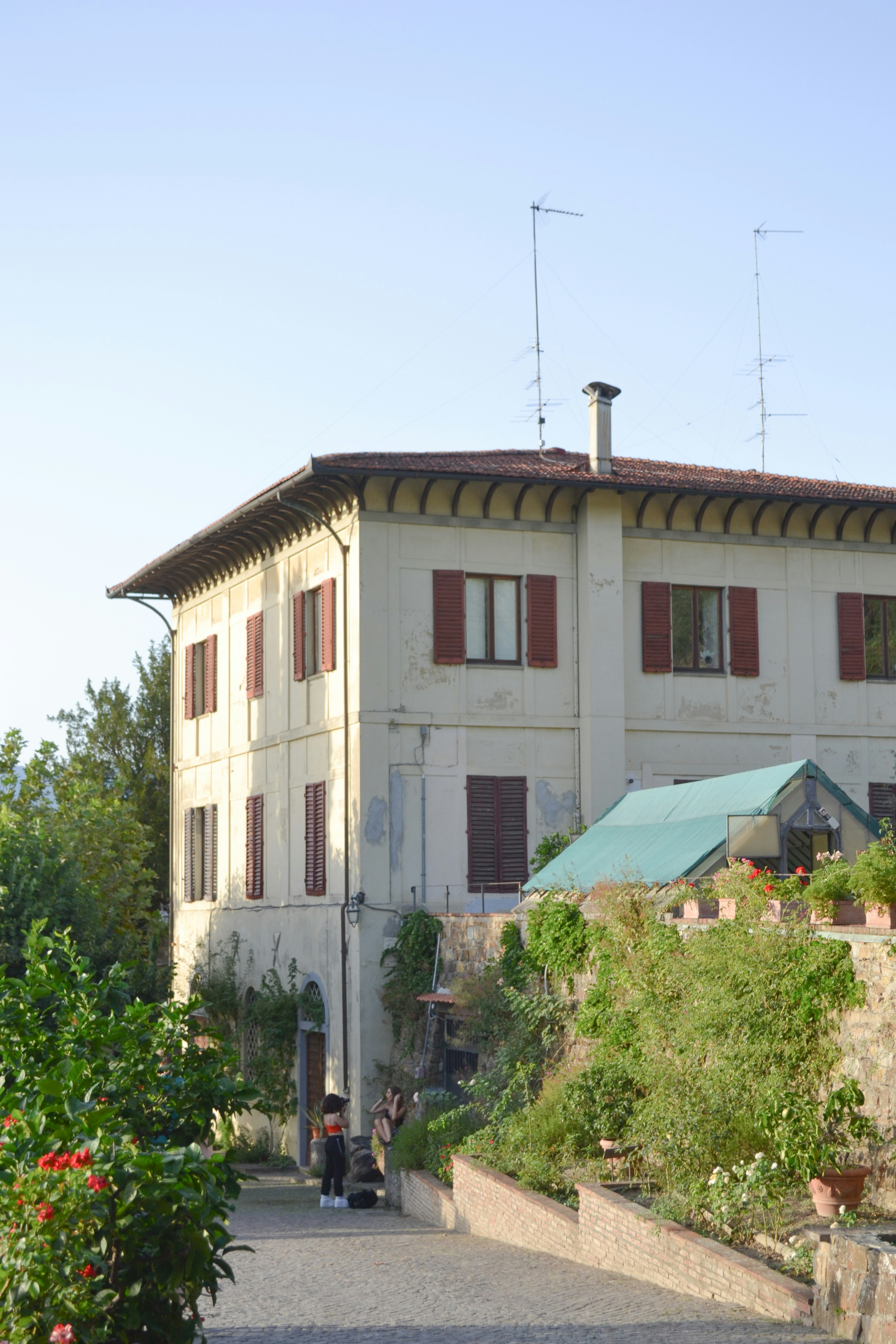 Charming historical building with faded walls and vibrant greenery in a serene courtyard setting.