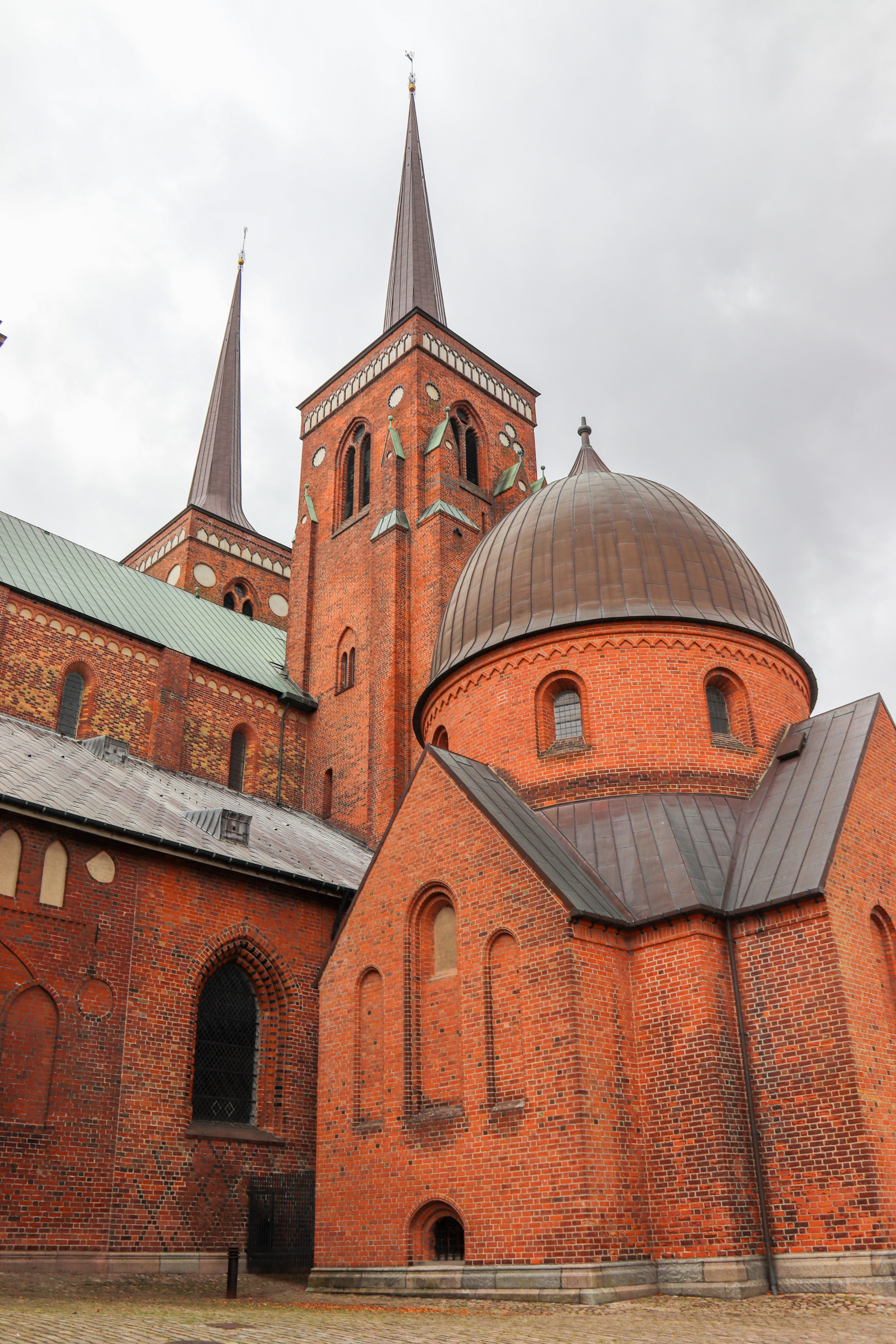 Historic red brick church with distinctive domes and spires under a cloudy sky.
