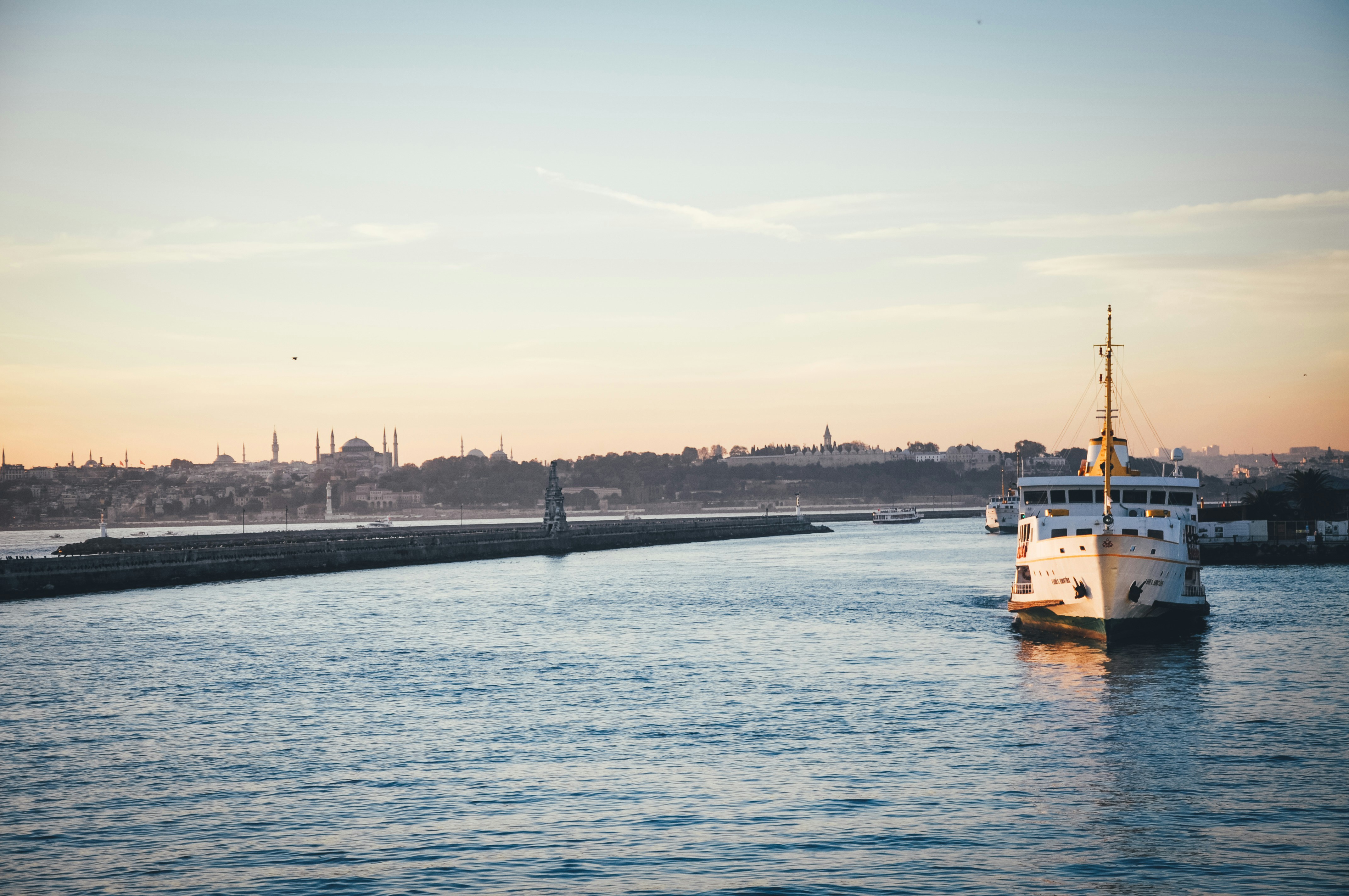 Ferry navigating the tranquil waters of the Bosphorus at dusk, with Istanbul's skyline softly illuminated in the background.