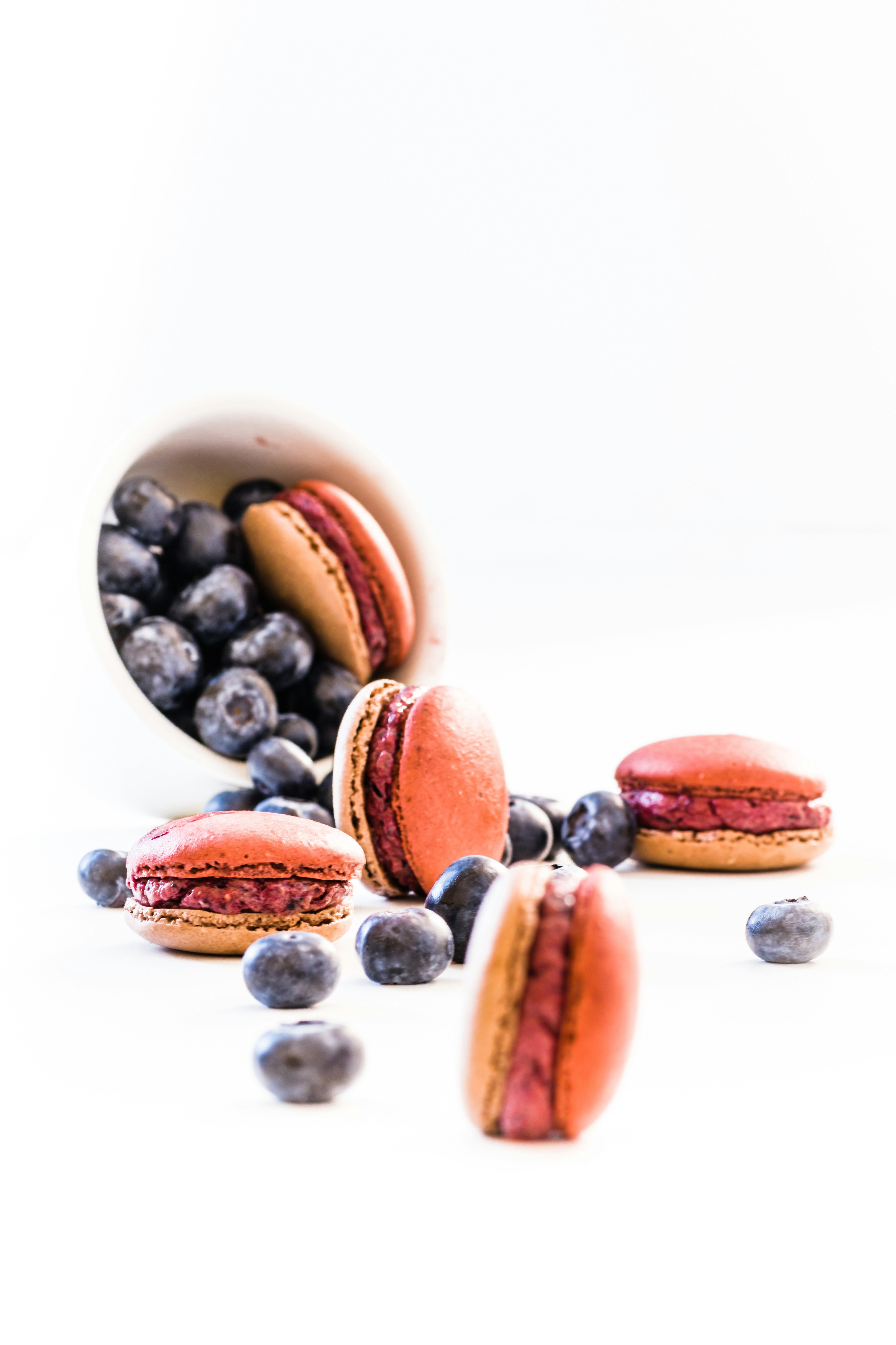High-Key Studio Still-Life: Coral Macarons Tumble Among Blueberries