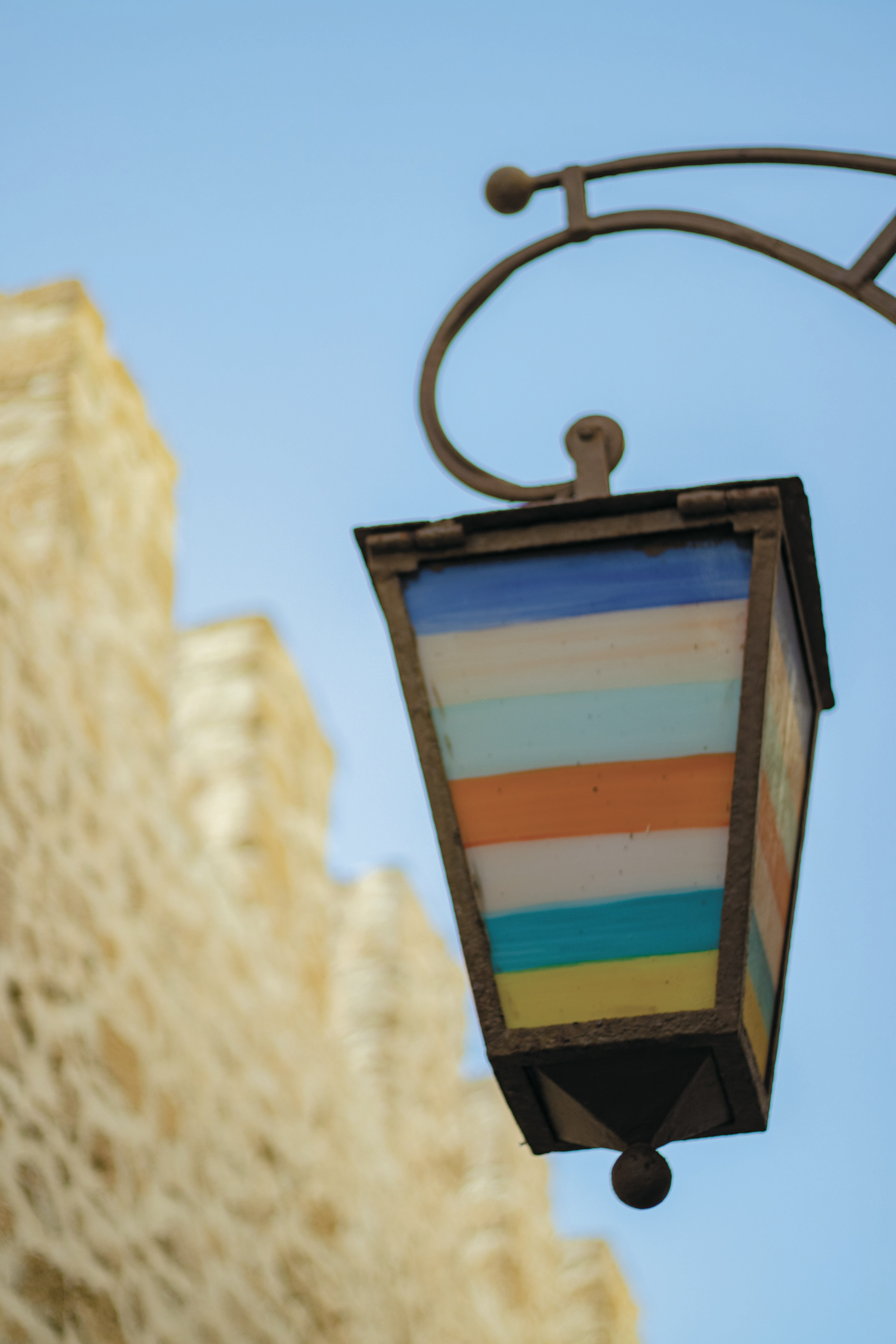 Striped Lantern Aglow Against Blue Sky and Weathered Stone