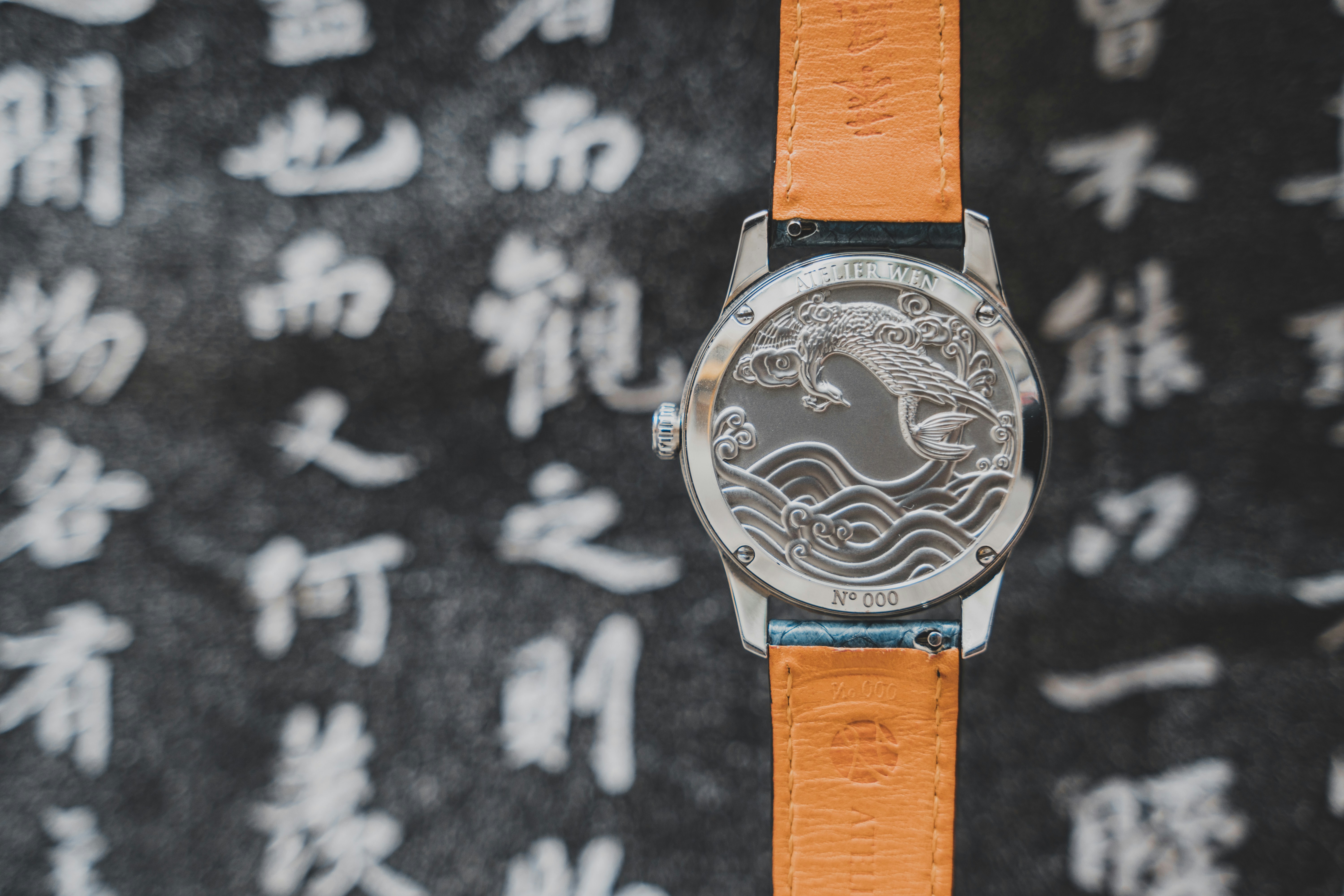 Copper-strap wristwatch with engraved back against dark script backdrop