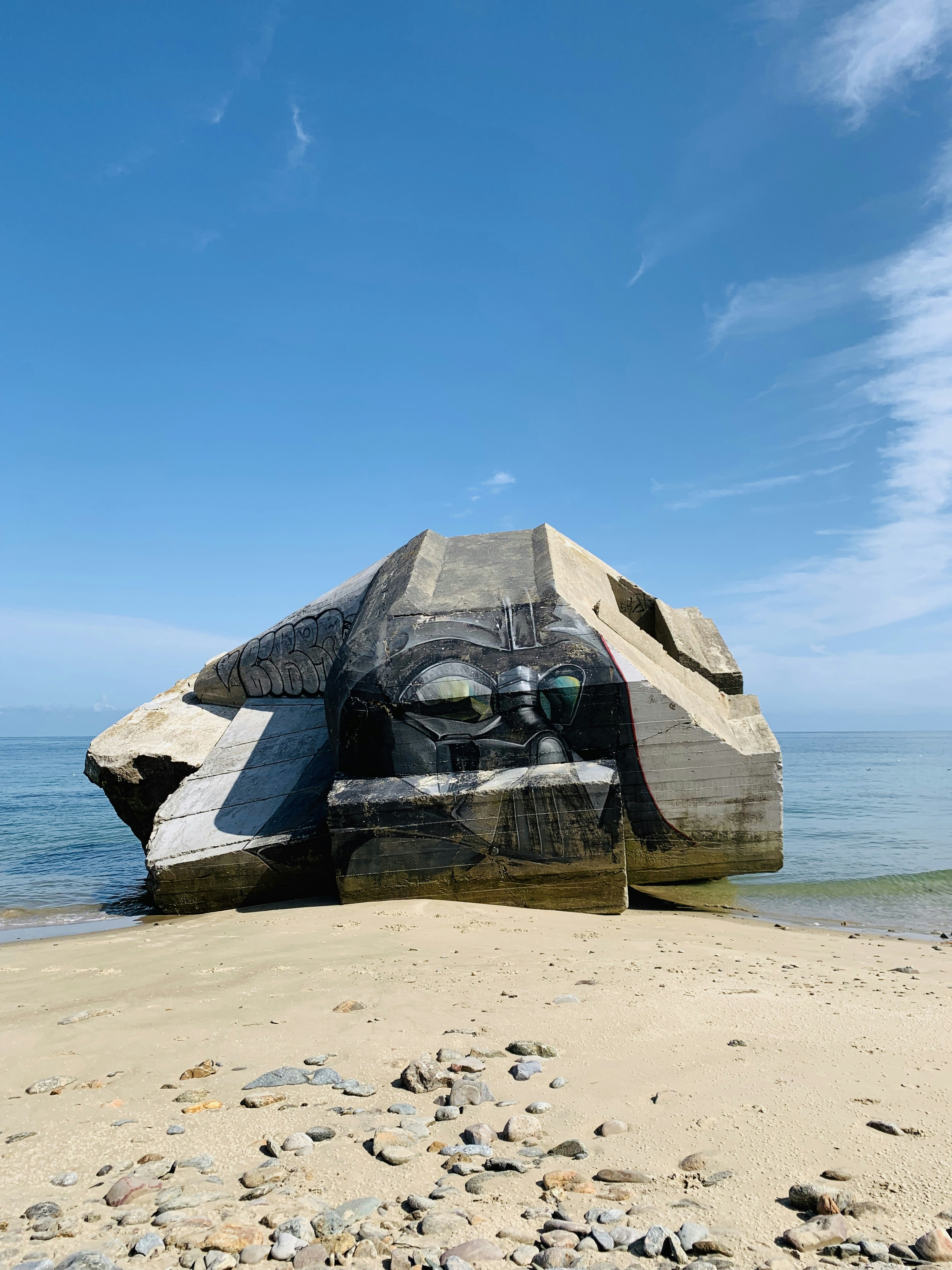 Graffitied Breakwater Mask Beneath the Open Sky