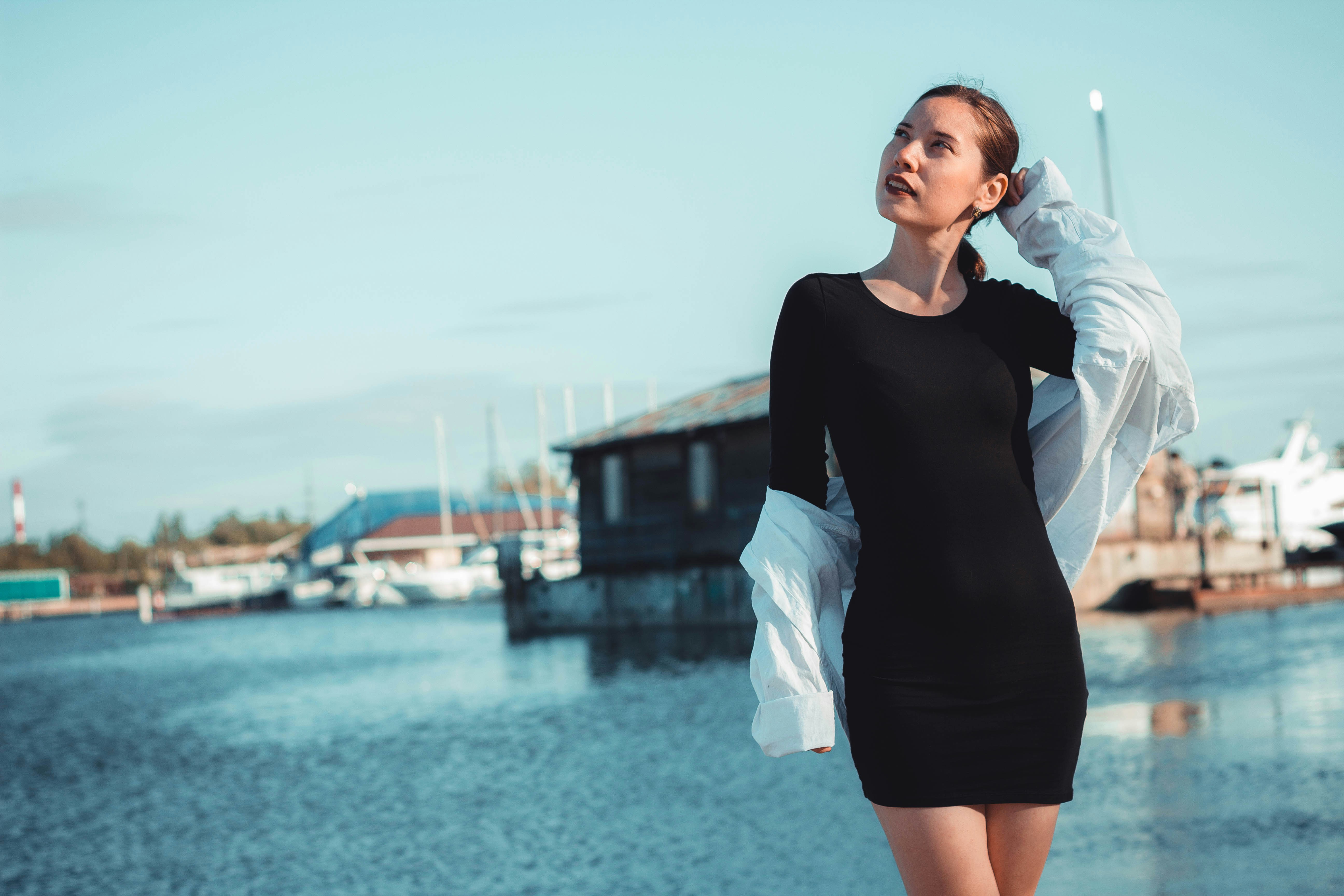 Woman standing and looking upwards in front of building above body of ...