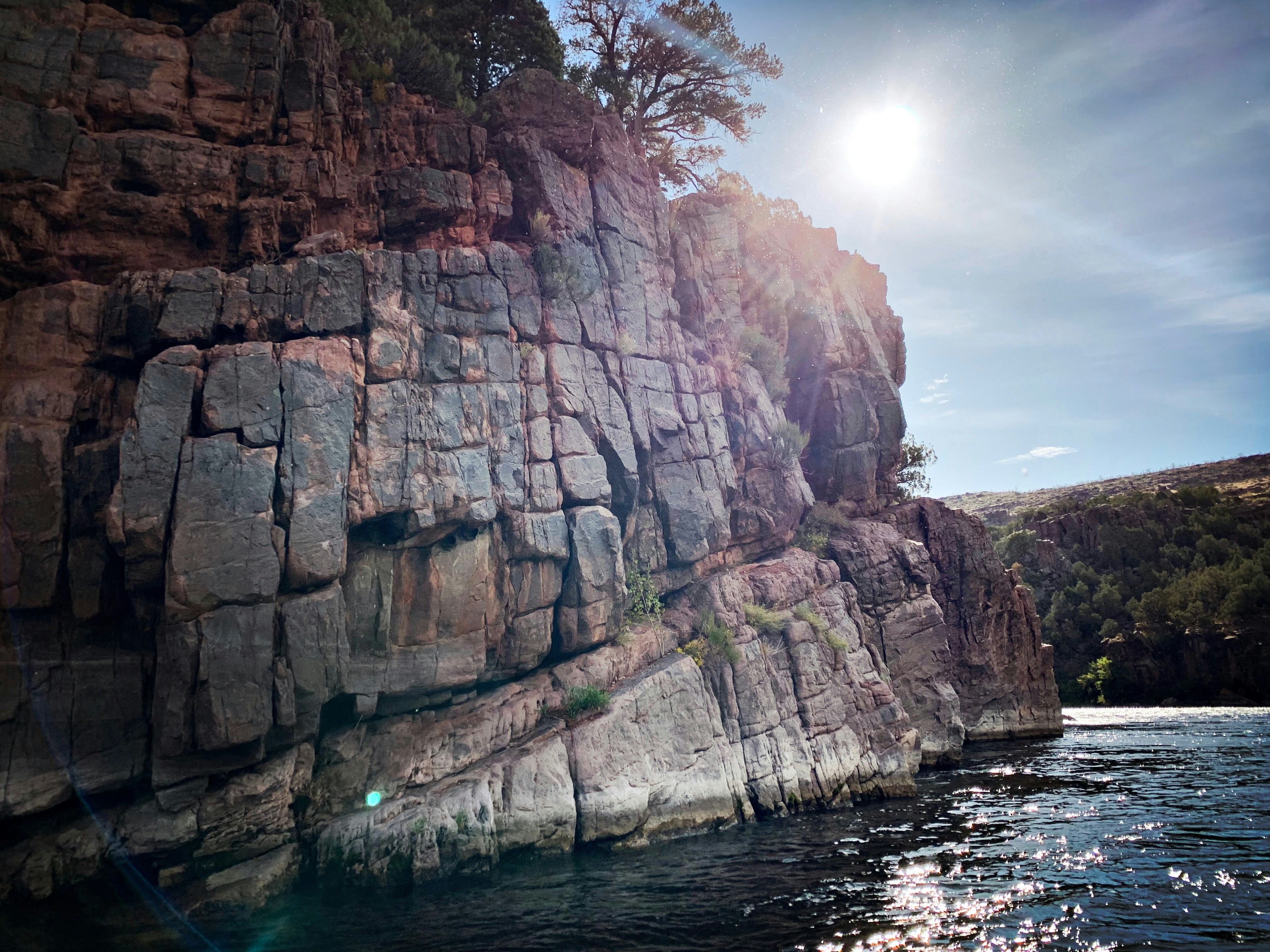 Sunlit basalt cliffs and glinting water at the lake edge