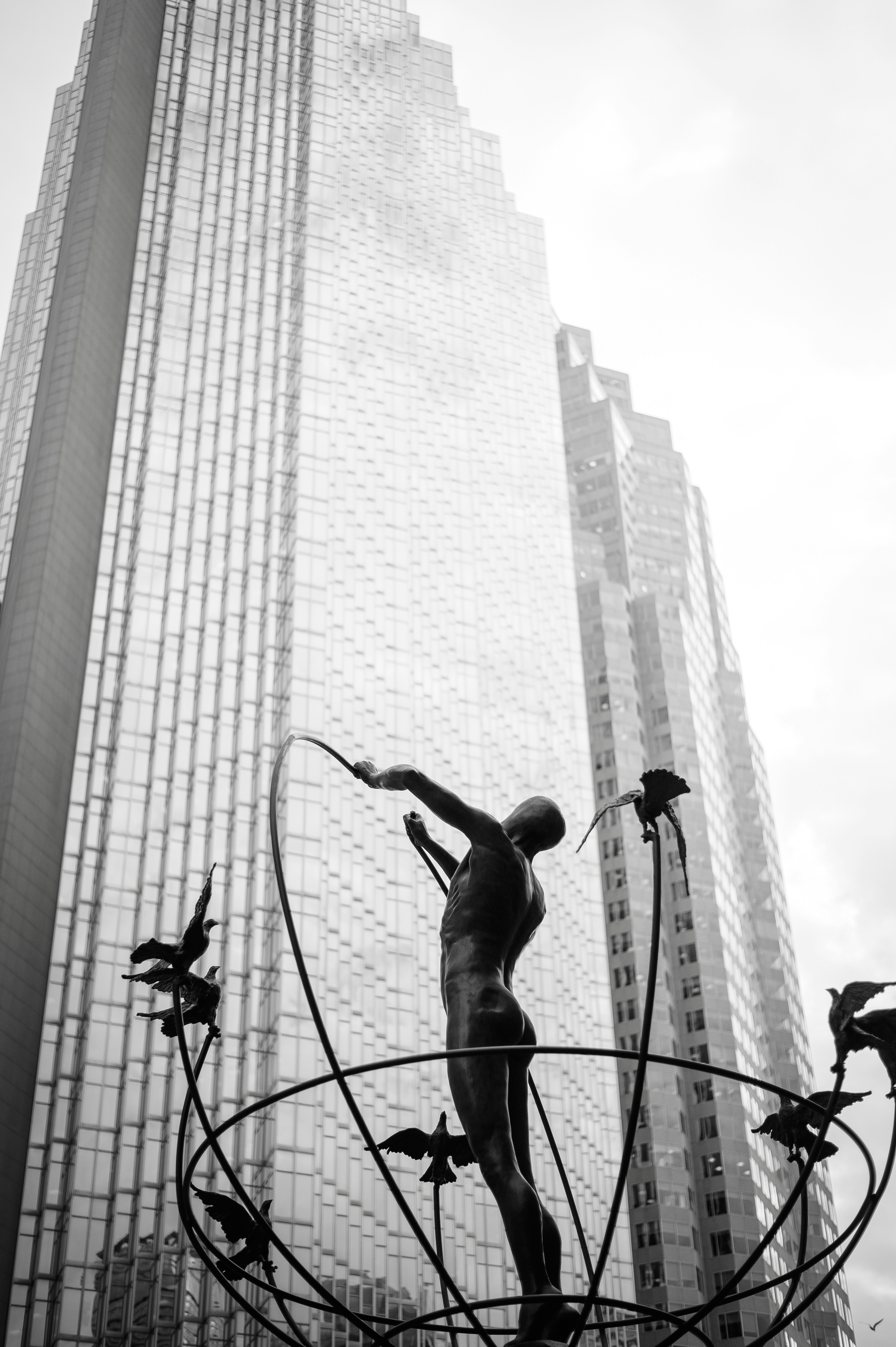 Urban Gravity: A Sculpted Figure Amid Skyscraper Rails