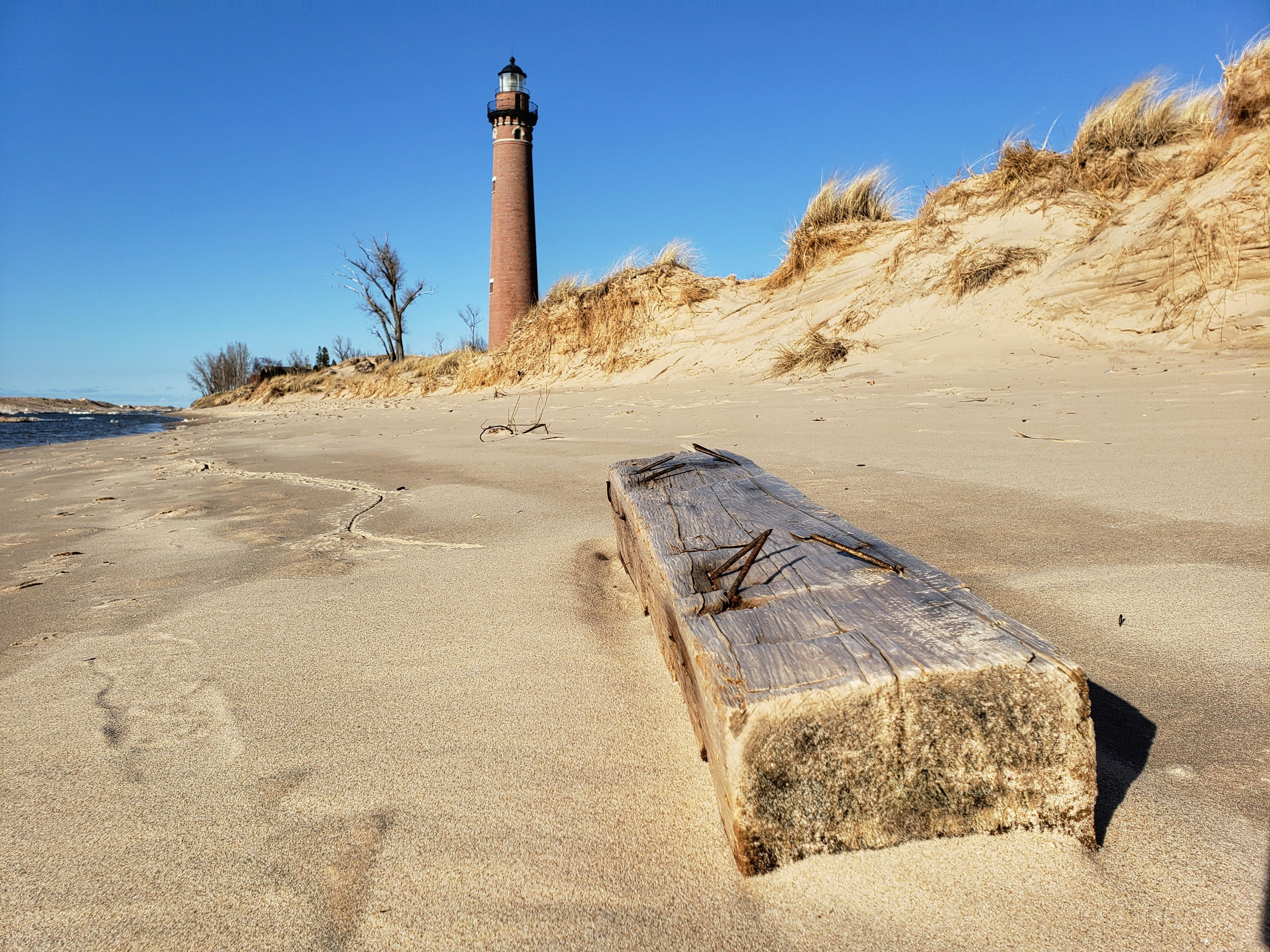 Beacon on the Wind-Whittled Dune: Lighthouse Framed by Sea and Sand
