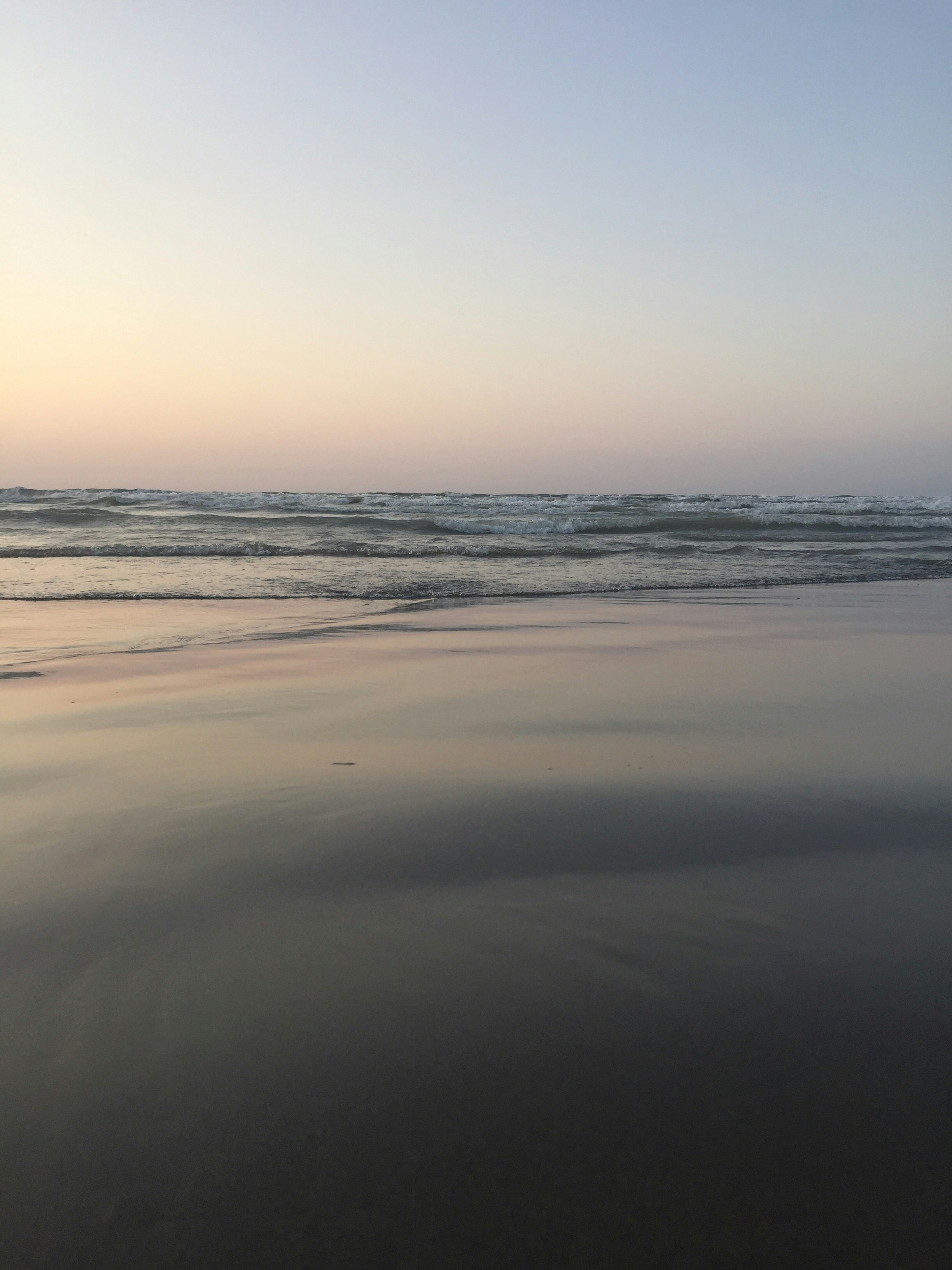 Gentle waves lapping against a serene shoreline at twilight, reflecting soft hues of the setting sun.