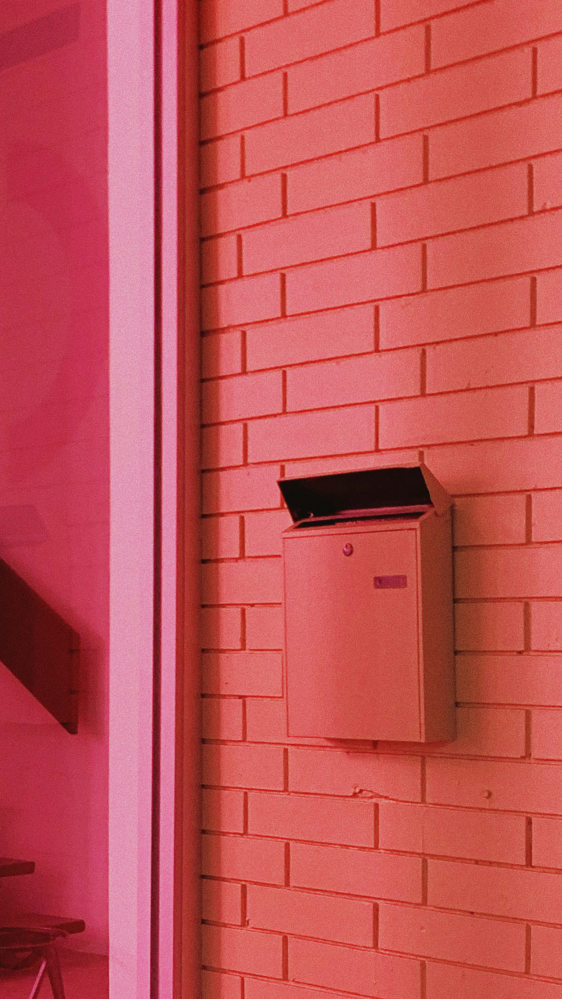 Magenta Glow on a Brick Facade: The Wall-Mounted Mailbox