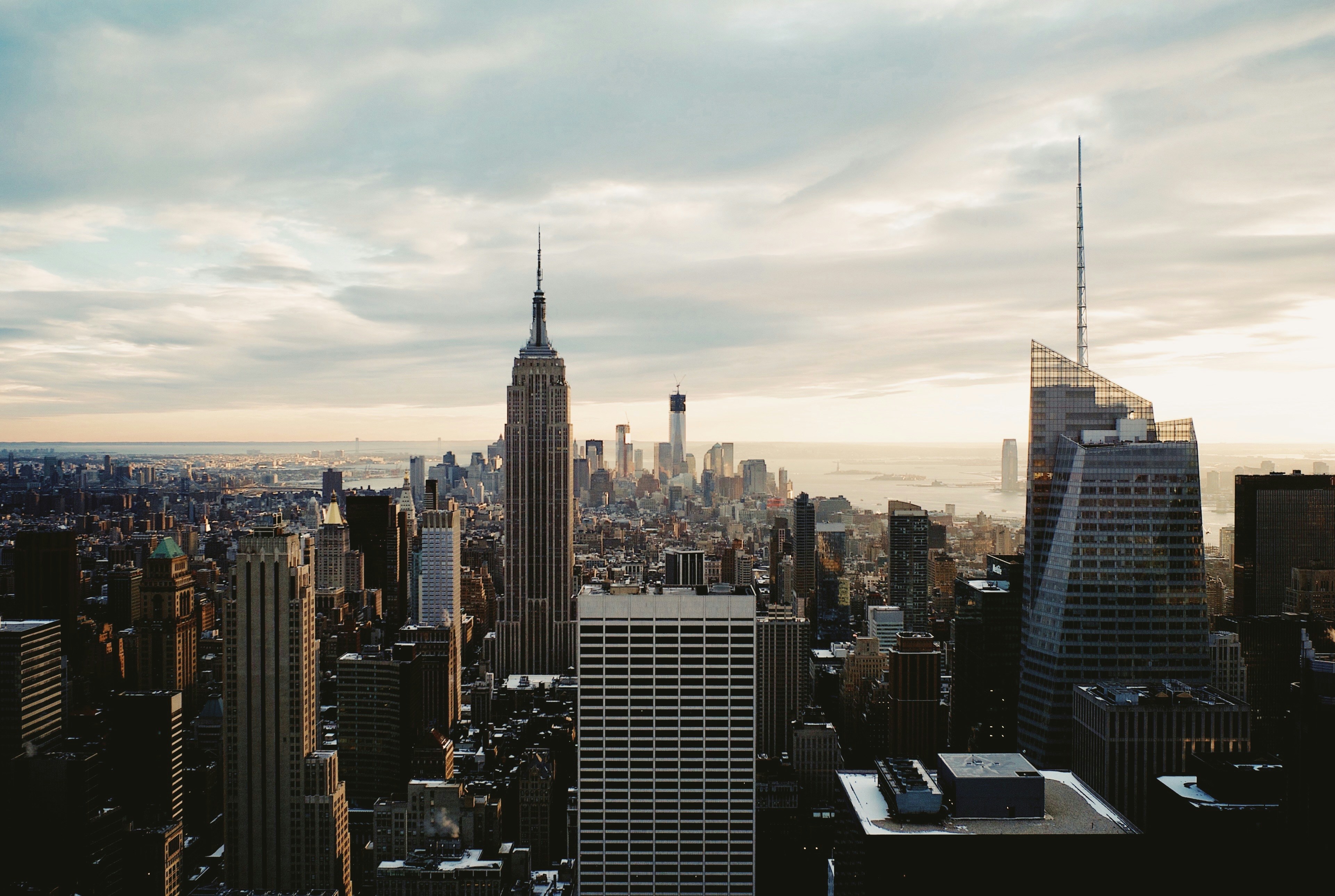 A panoramic view of New York City, showcasing the iconic Empire State Building amidst a tapestry of skyscrapers under a soft twilight sky.