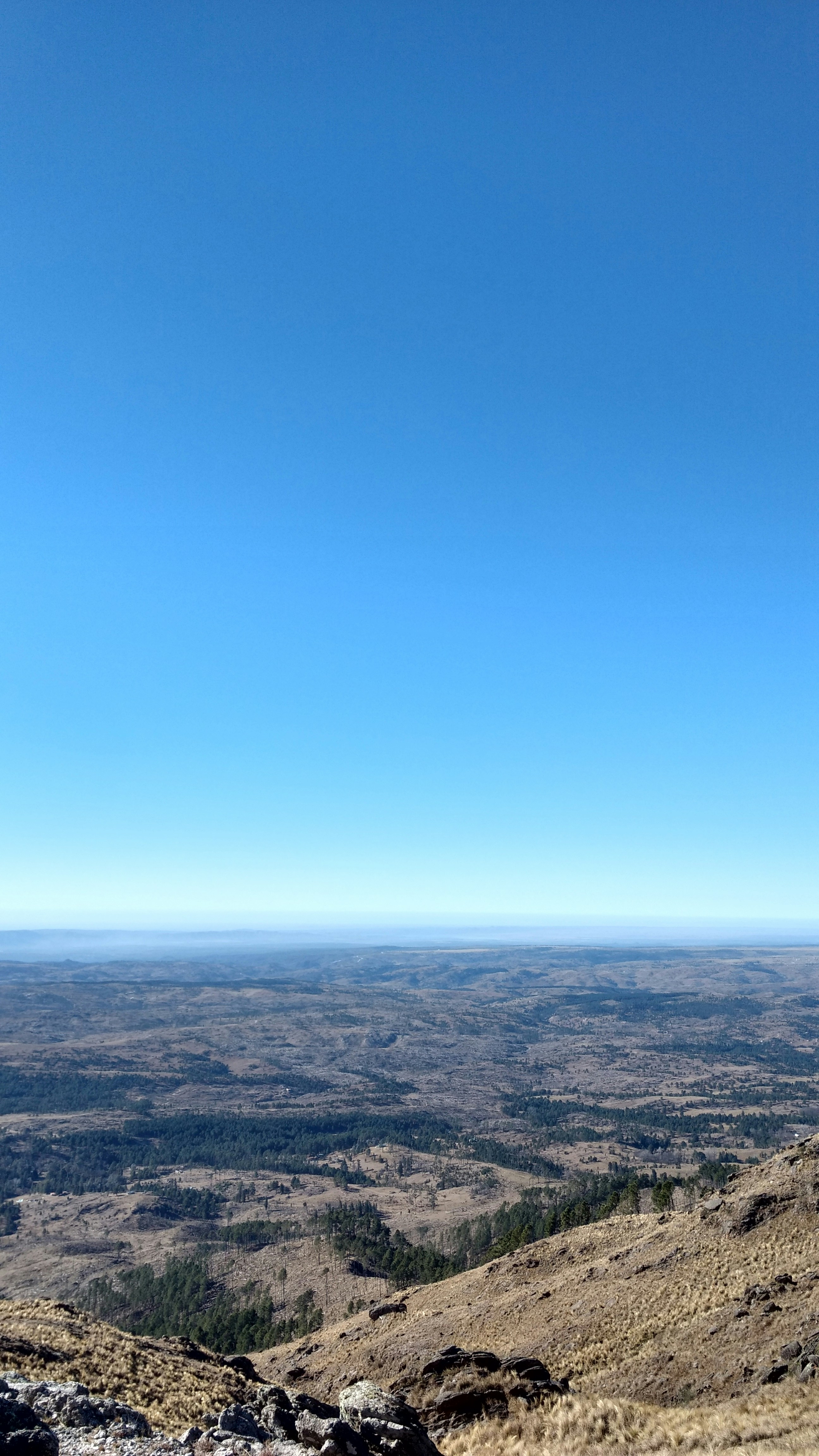 Expansive view of rolling hills and valleys under a clear blue sky, showcasing the serene beauty of nature.