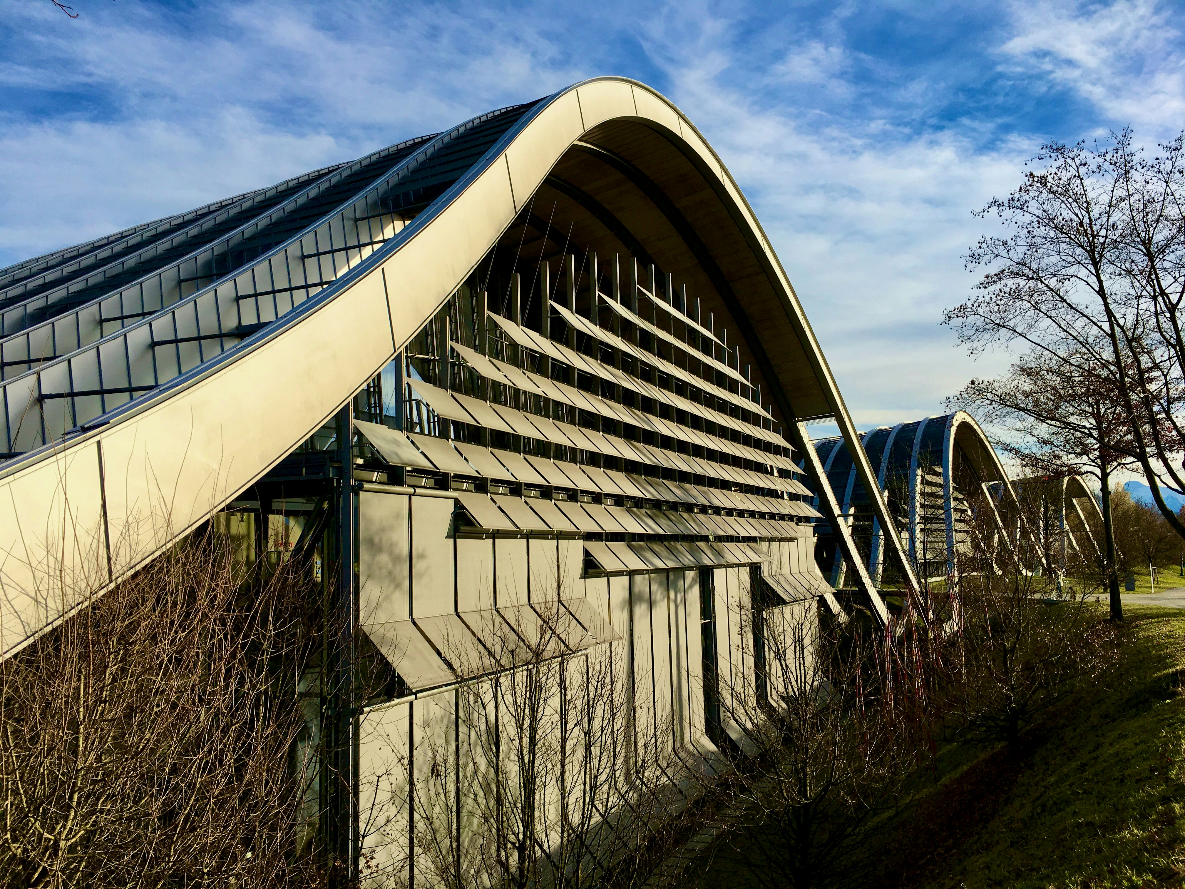 Modern architectural structures with sweeping curves and glass facades, framed by sparse vegetation and a clear blue sky.