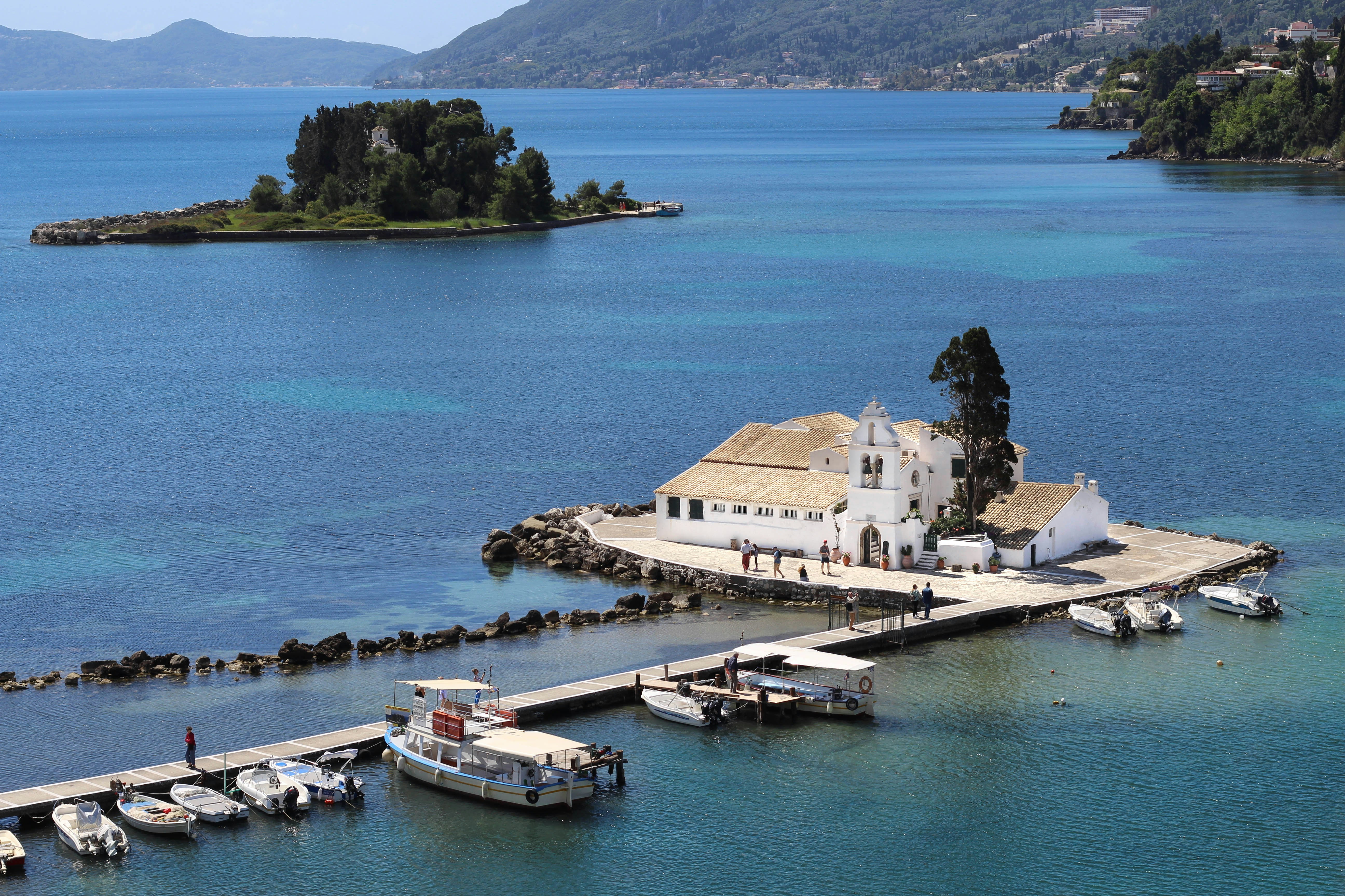 White Chapel at the End of a Turquoise Pier in a Tranquil Aegean Harbor
