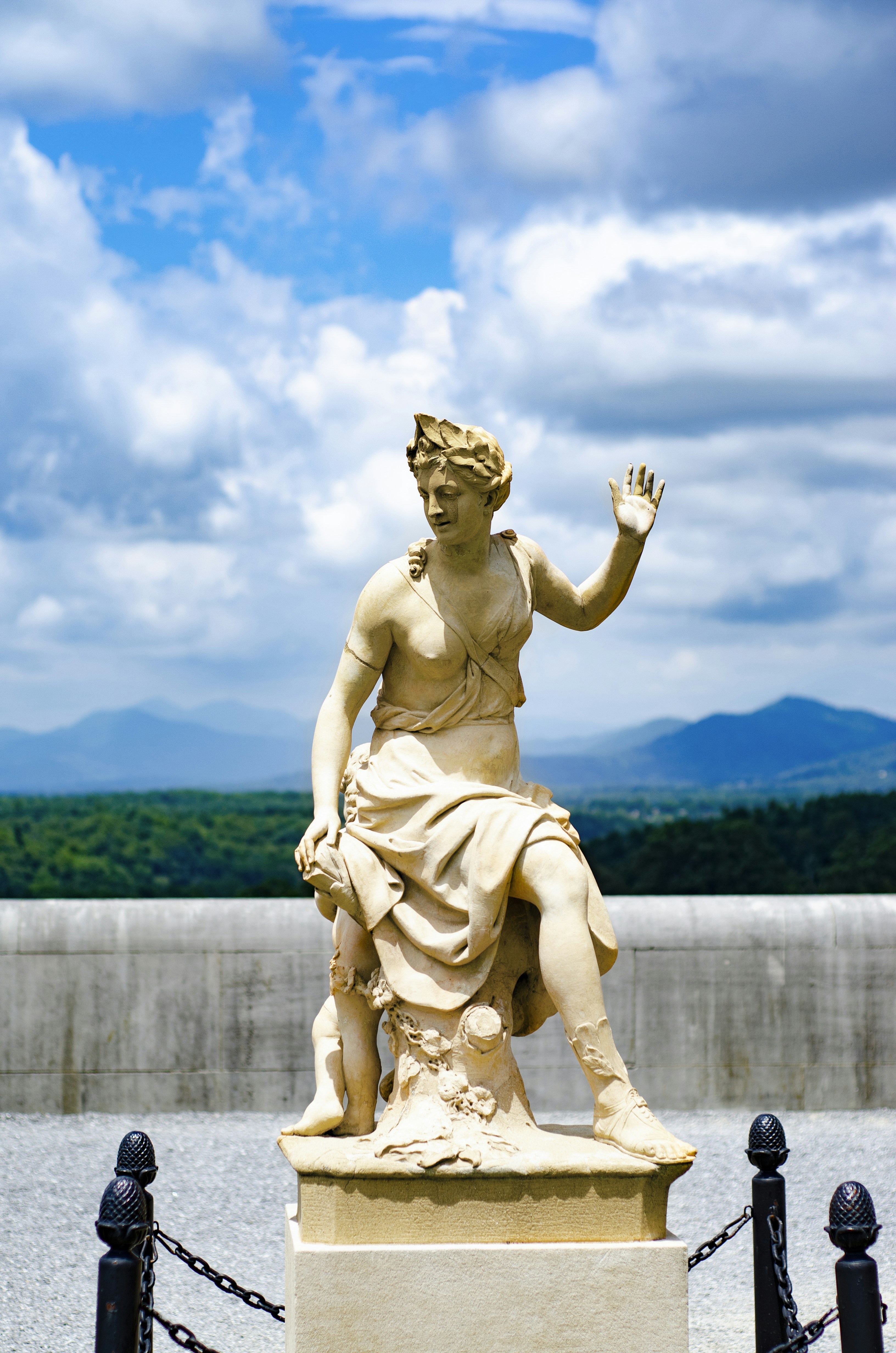 Seated Sentinel Under a Cobalt Sky: Marble Figure Framed by Mountains