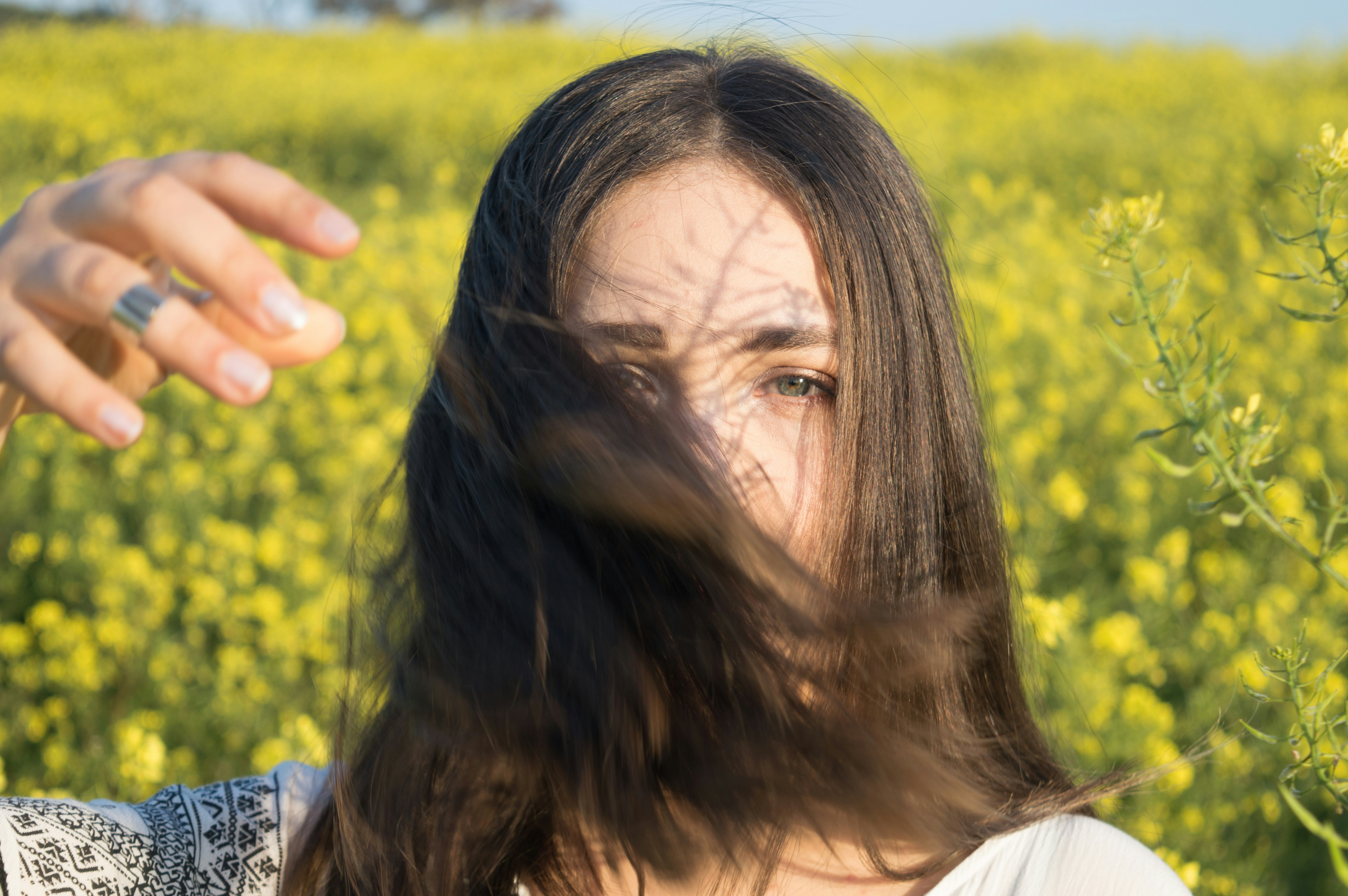 A young woman playfully tossing her hair in a vibrant field of yellow flowers, capturing the essence of joy and freedom.