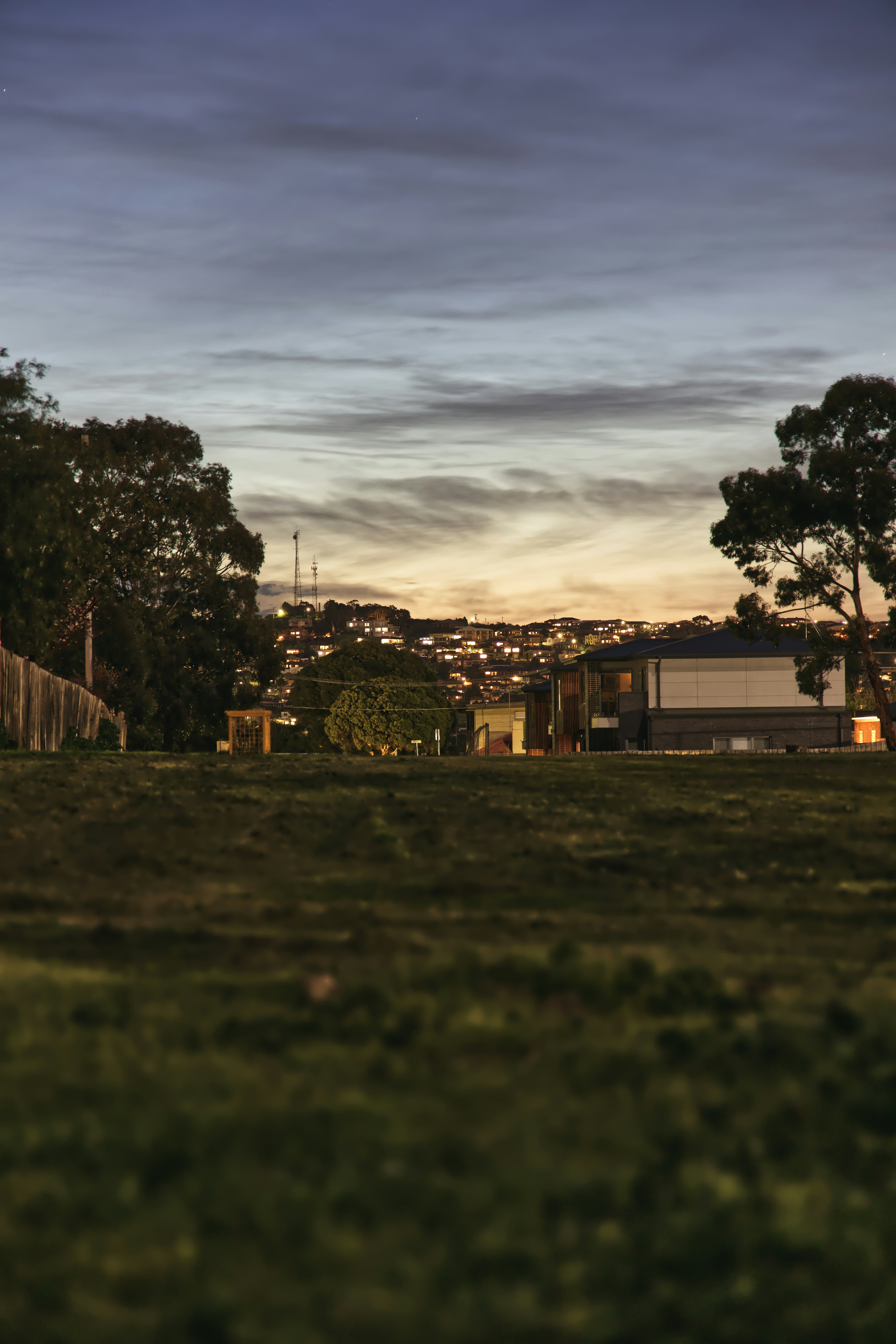 Quiet suburban landscape at twilight, showcasing illuminated homes against a softly colored sky.