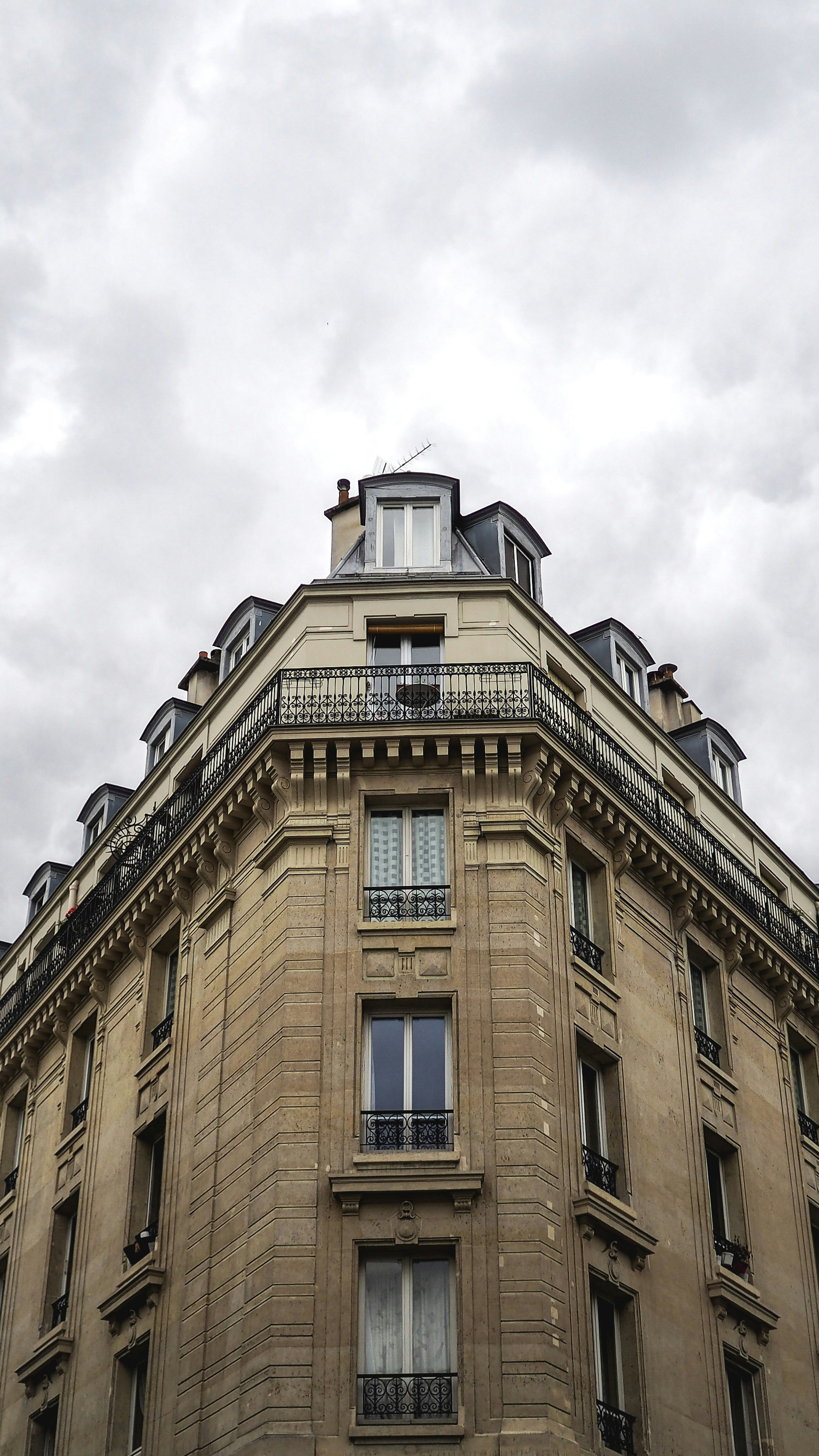 Historic Parisian building showcasing intricate architectural details and a classic facade under a cloudy sky.
