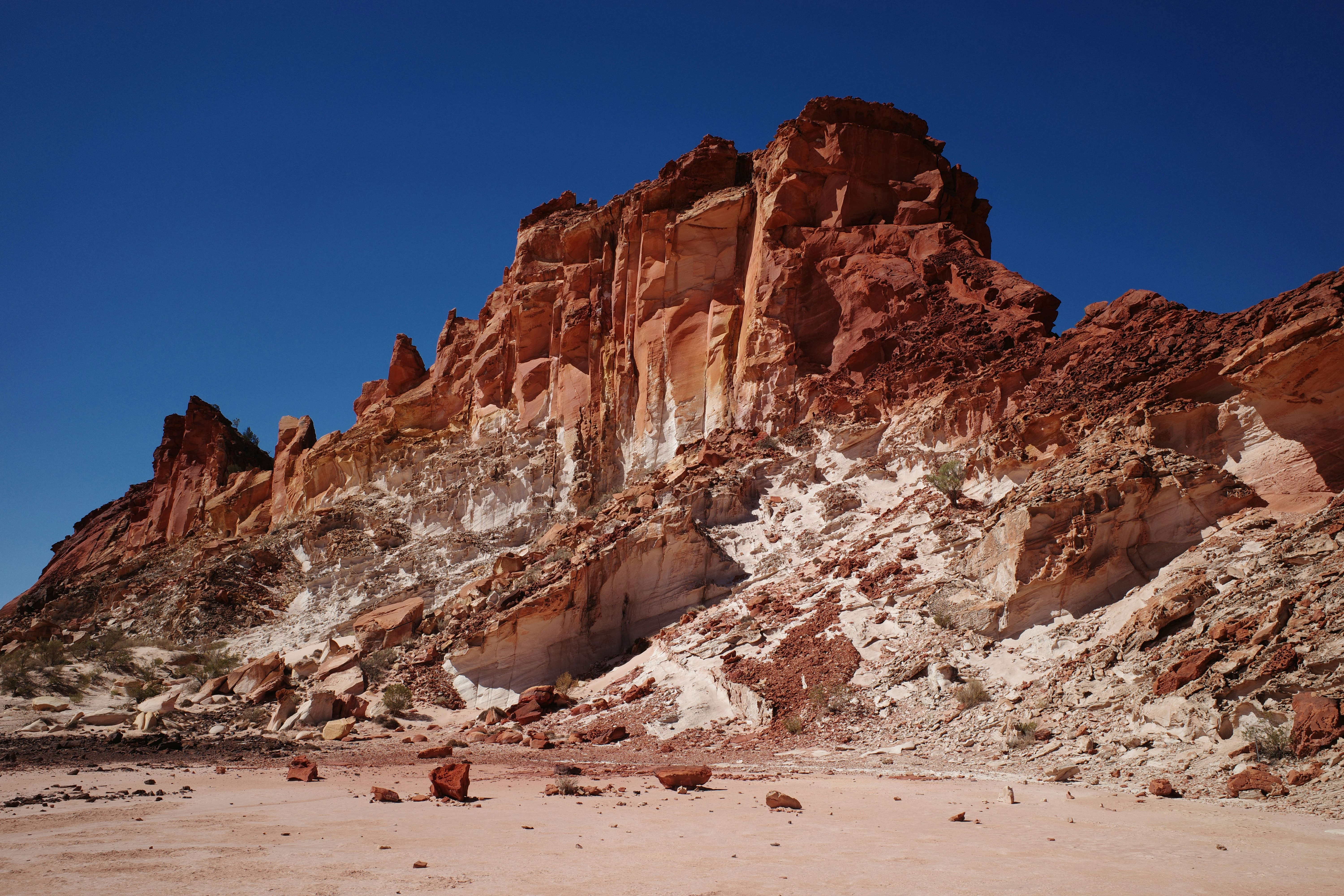 Vibrant red and white rock formations under a clear blue sky in a desert landscape.