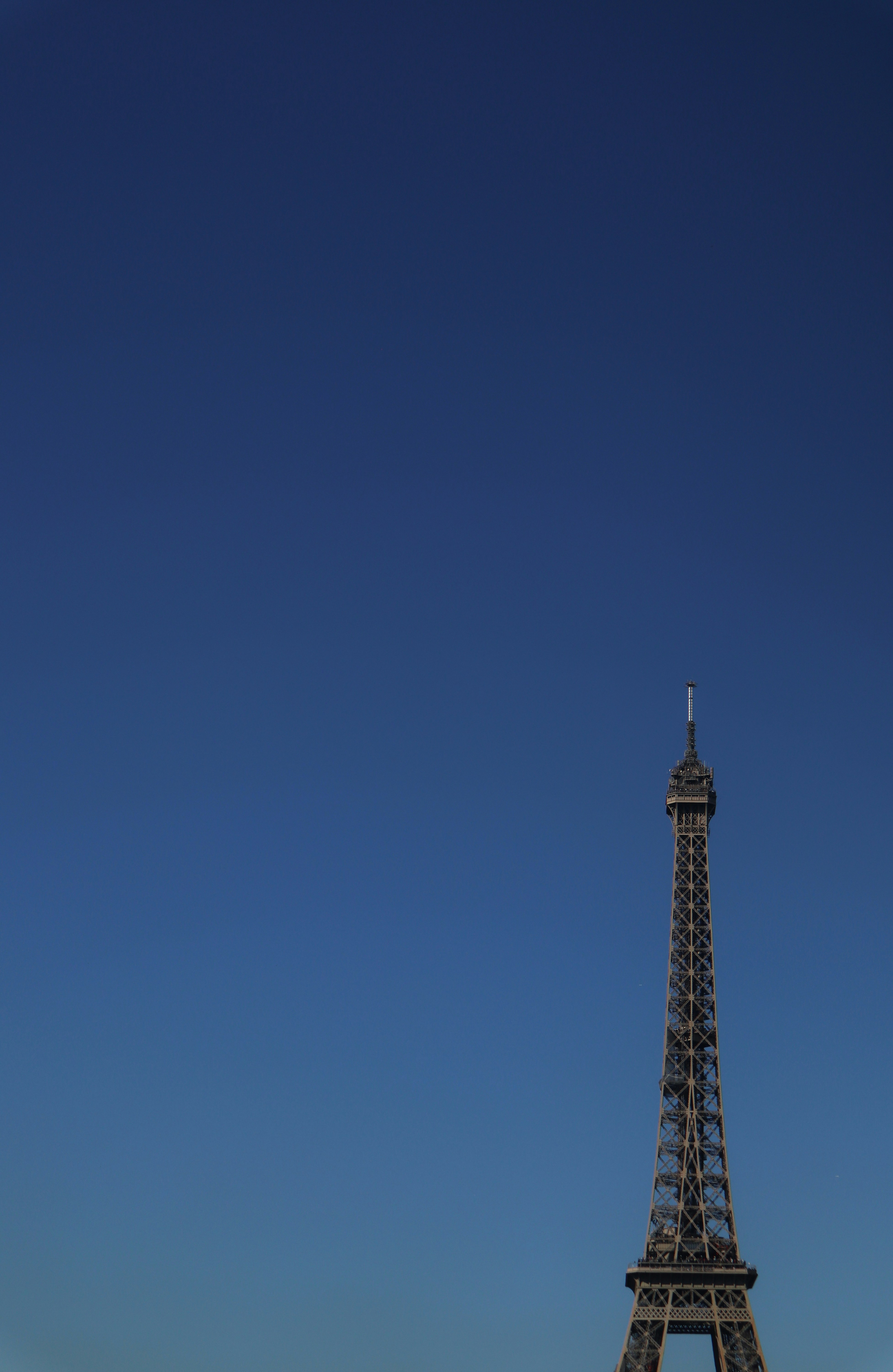 Eiffel Tower silhouetted against a clear blue sky, showcasing its intricate iron lattice structure.