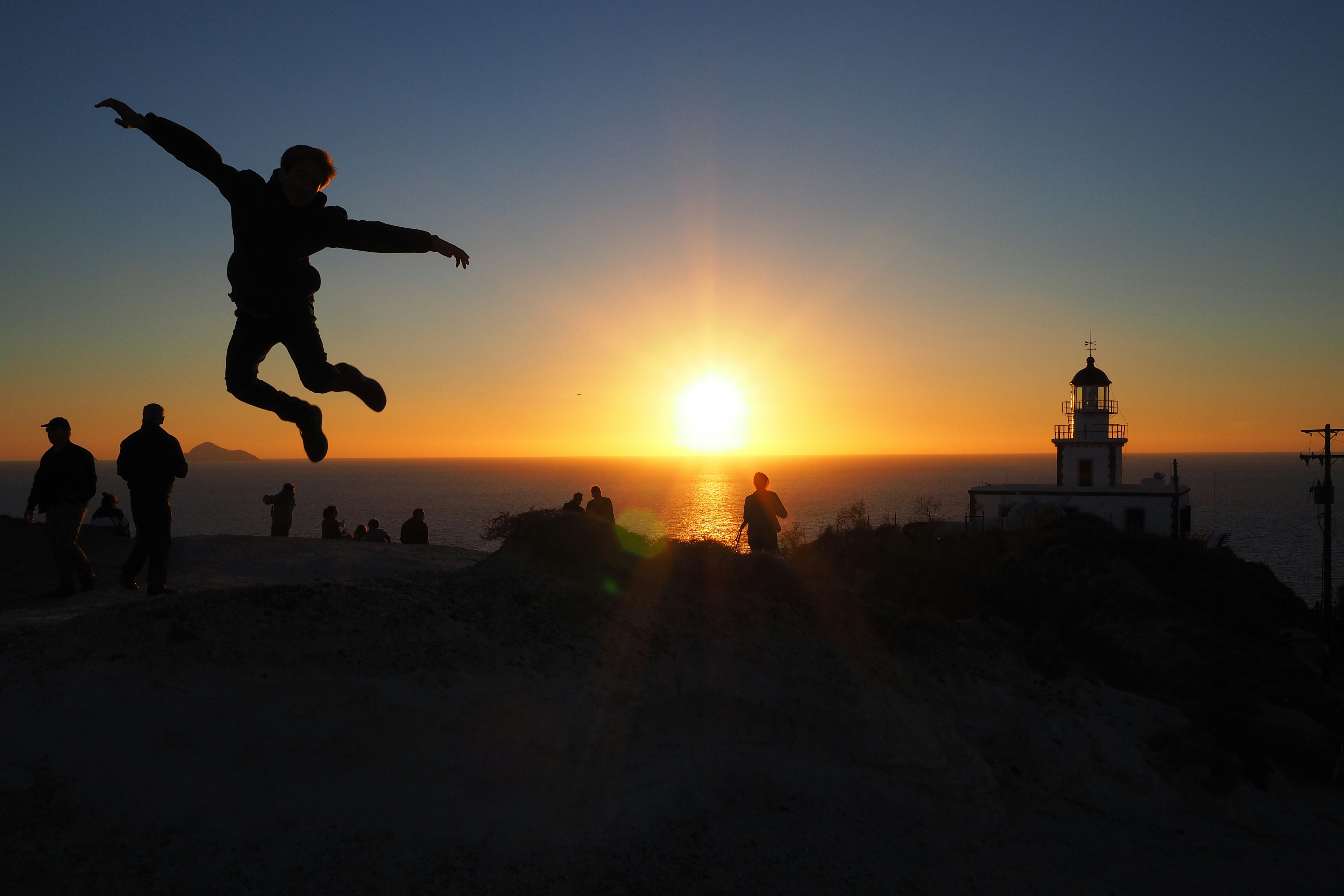 Silhouette Leap at Sunset Over a Coastal Lighthouse