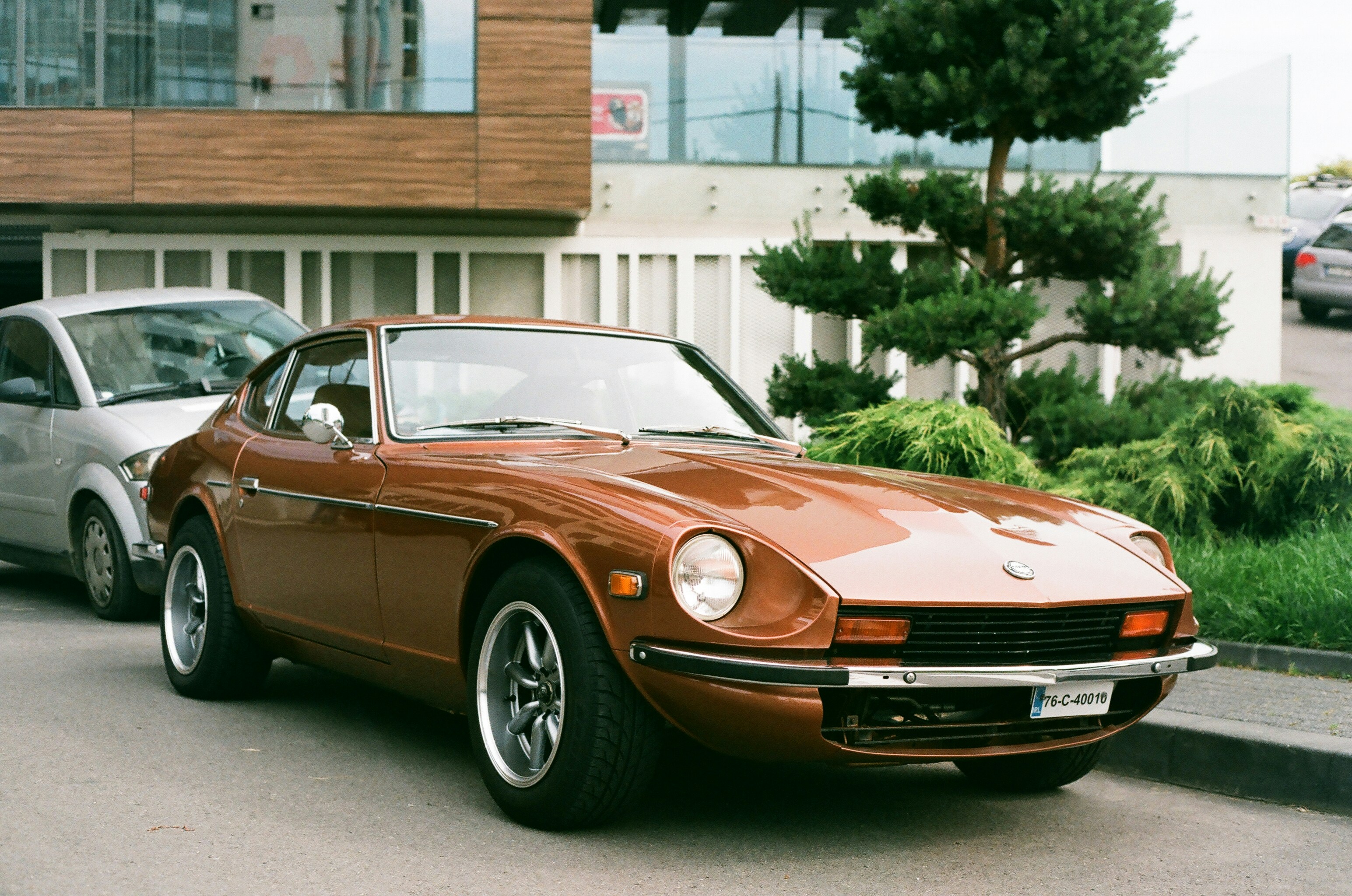 A vintage Datsun 240Z parked alongside modern vehicles, showcasing its iconic design against a contemporary backdrop.