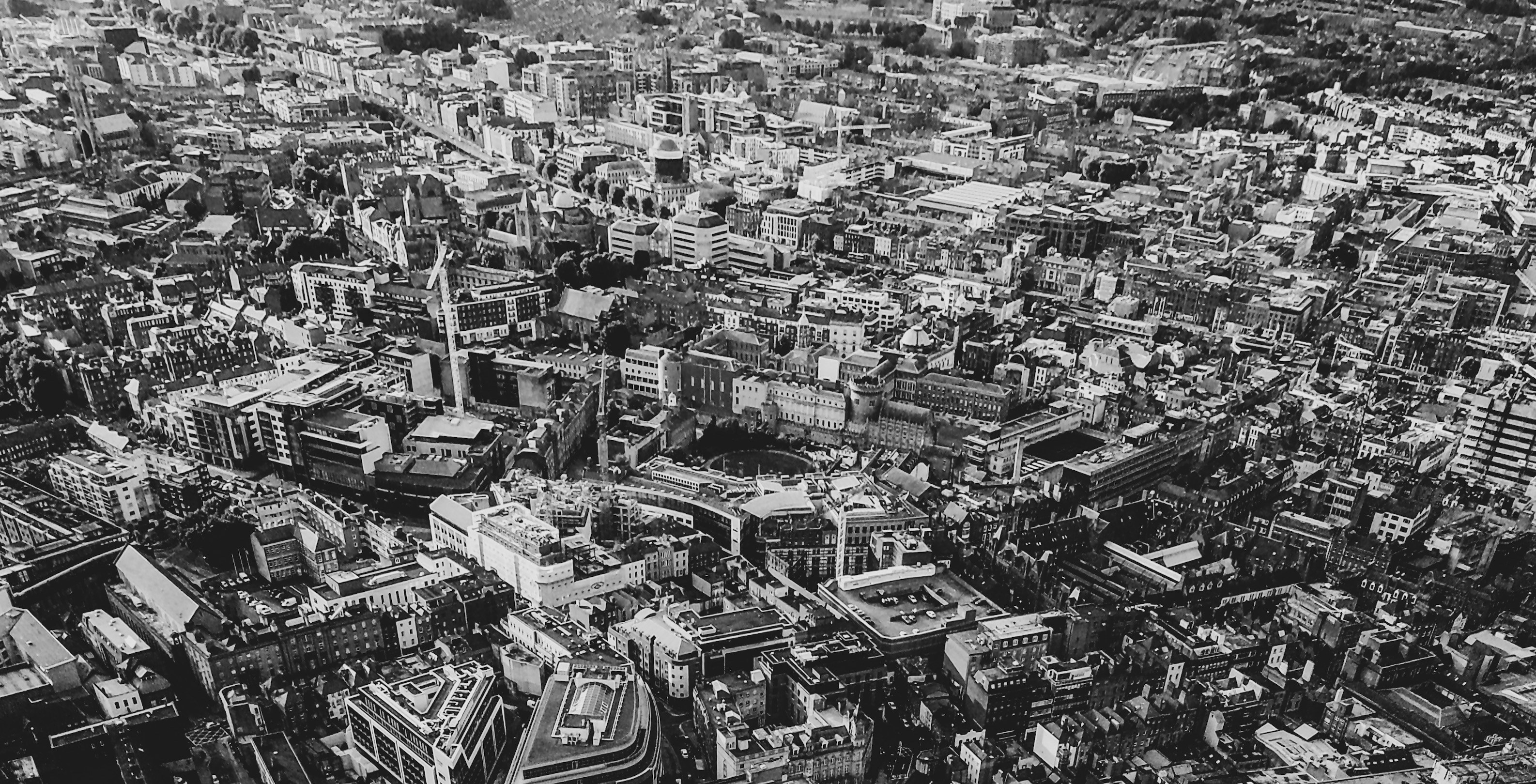 Aerial view of a bustling cityscape in black and white, showcasing intricate patterns of buildings and streets.