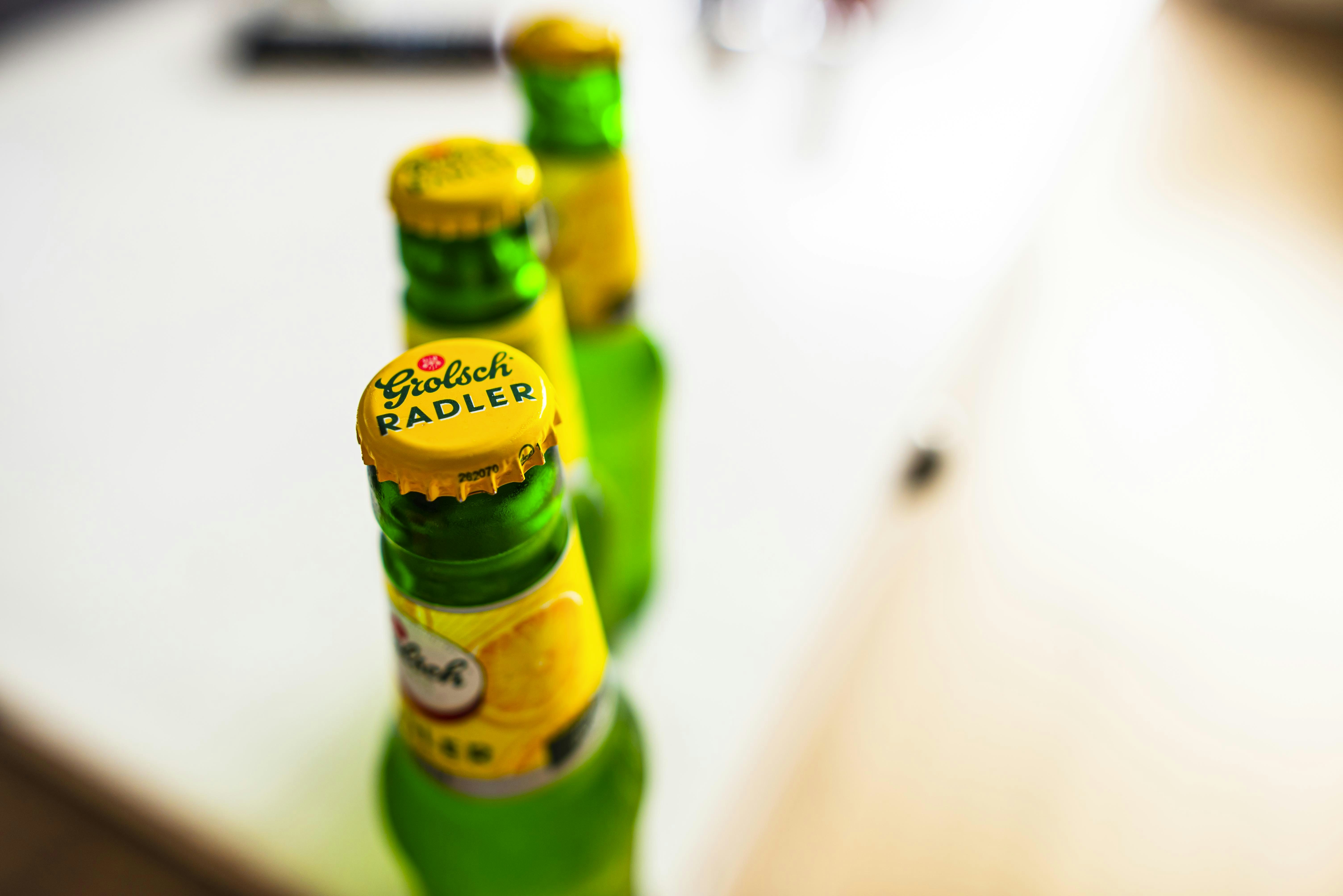 Close-up of Grolsch Radler bottles with vibrant green glass and distinctive caps, showcasing a casual beverage setting.