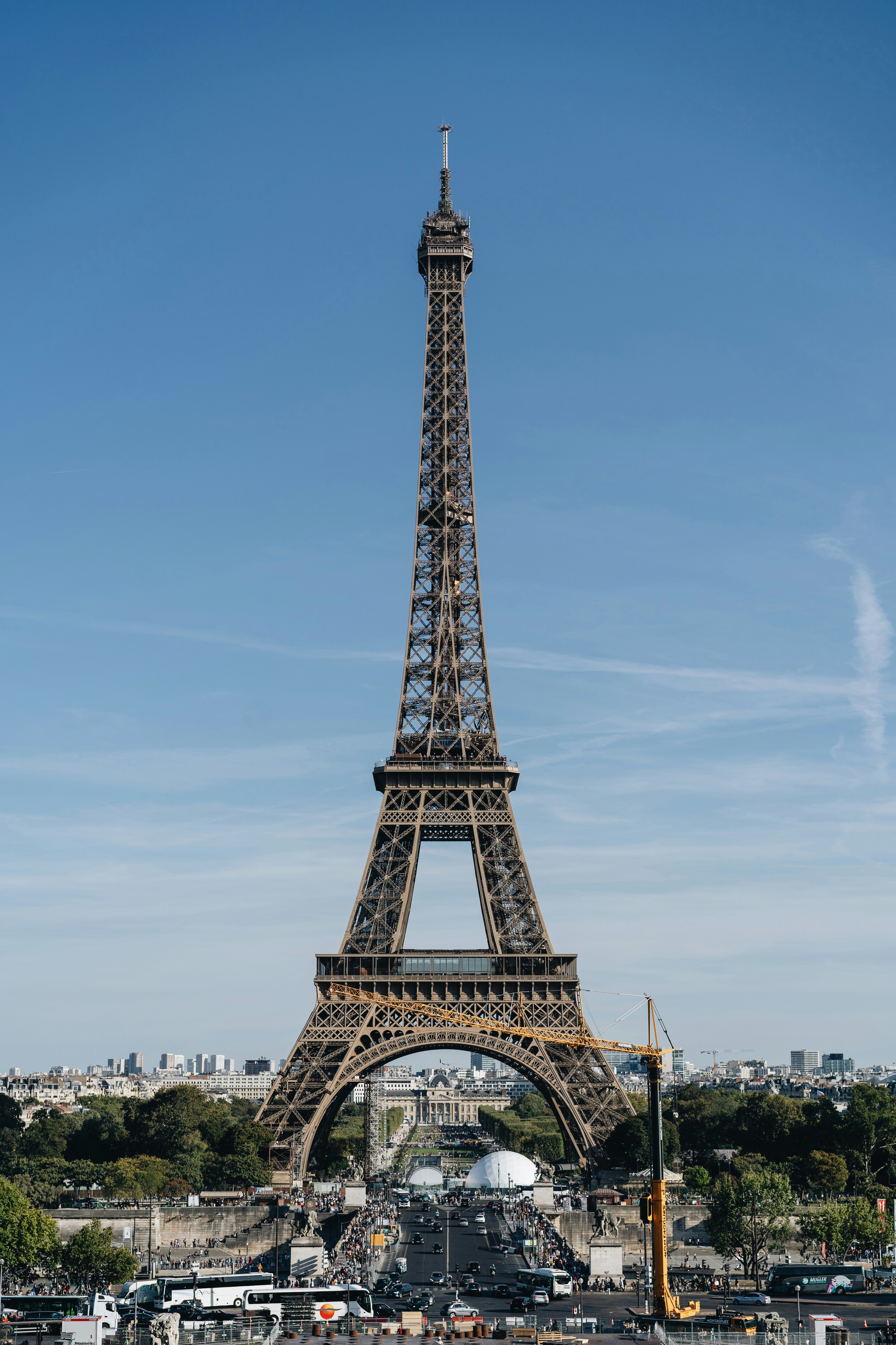 Eiffel Tower rising majestically above the Paris skyline, framed by a bright blue sky and bustling city life below.