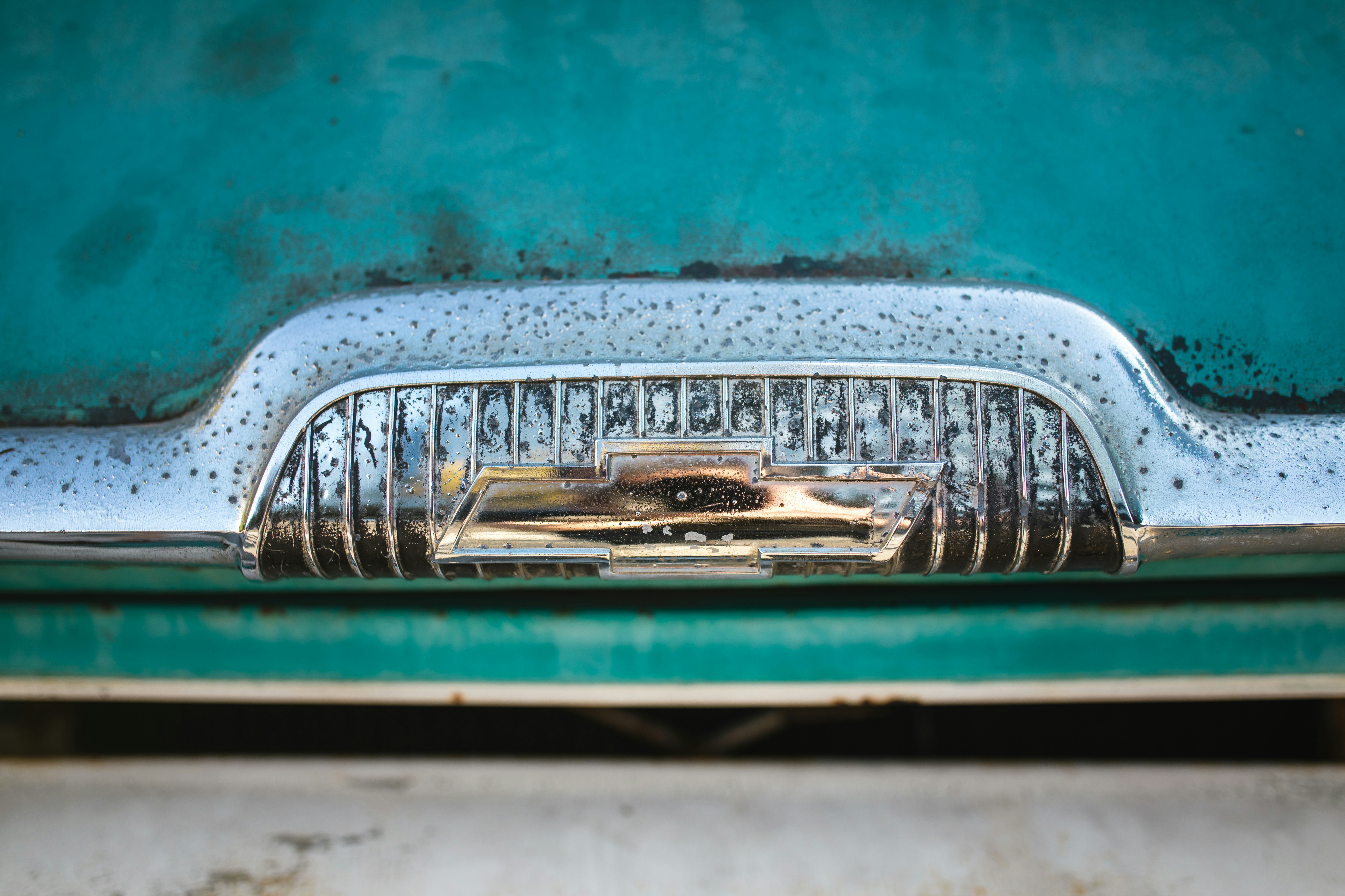Teal Vintage Chrome: Close-Up of a Mid-Century Car Grille and Emblem