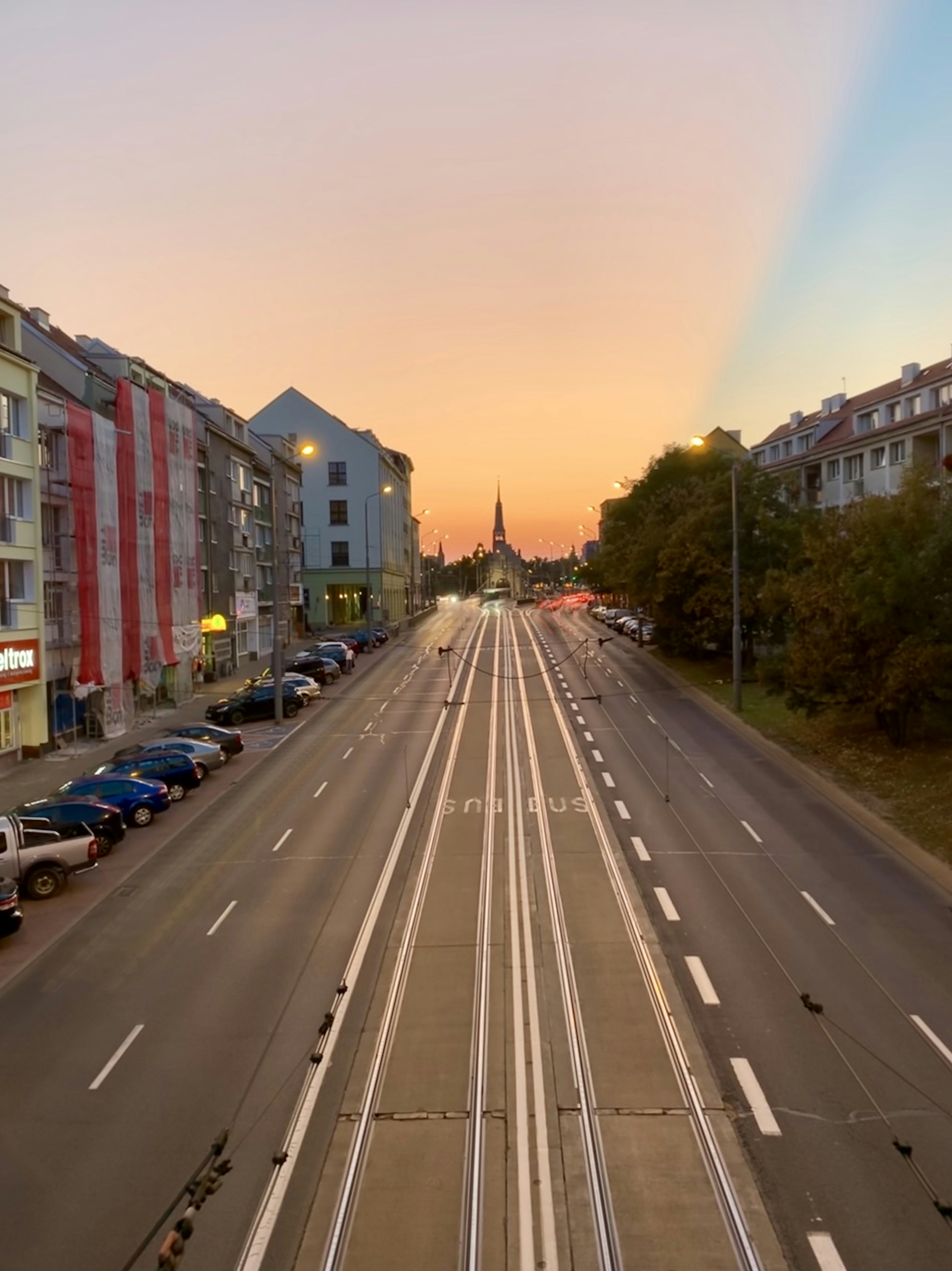 Evening Convergence: Tram Rails Lead Toward a City Spire