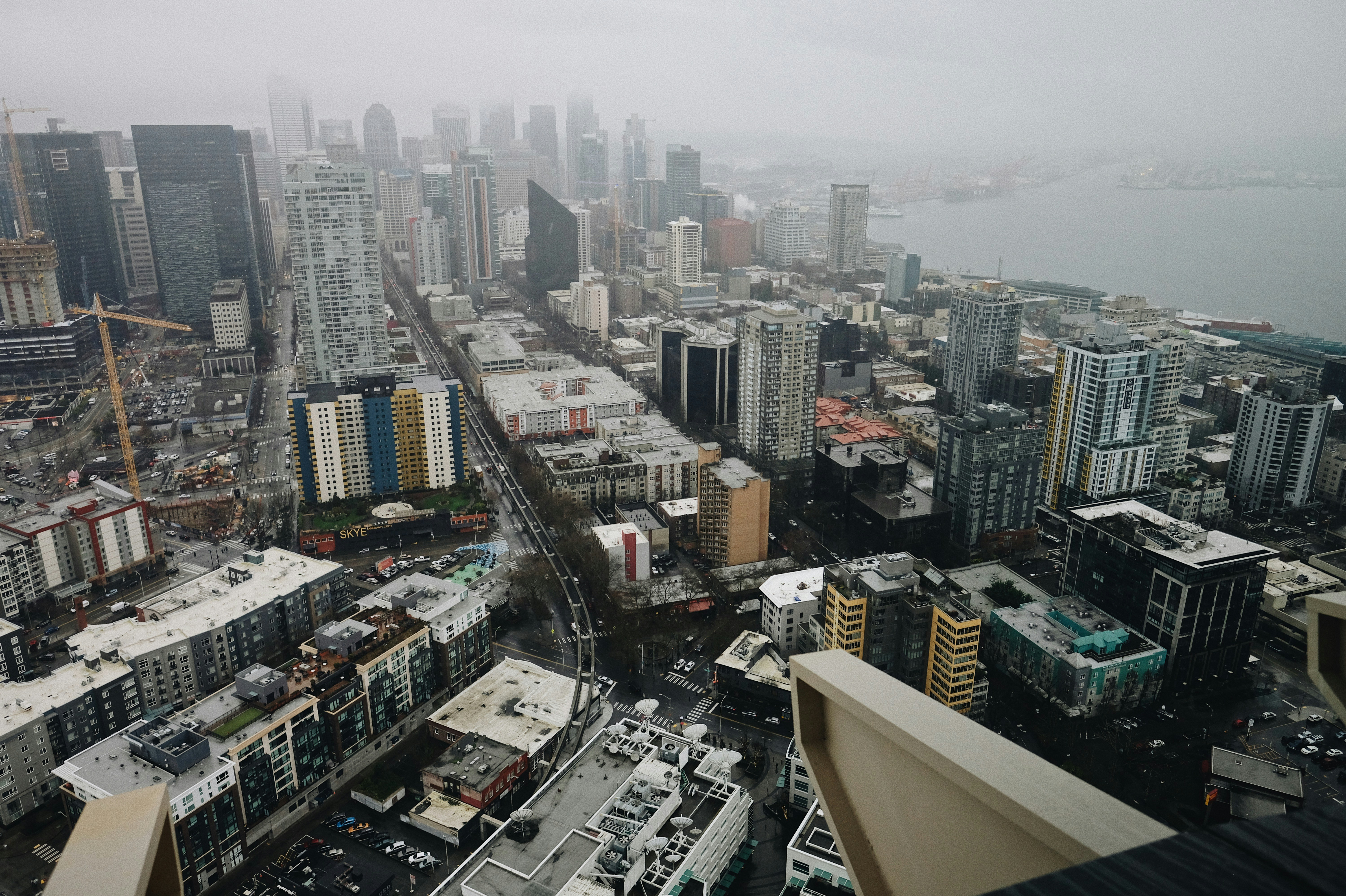Aerial view of a dense cityscape with tall buildings and distant foggy skyline.