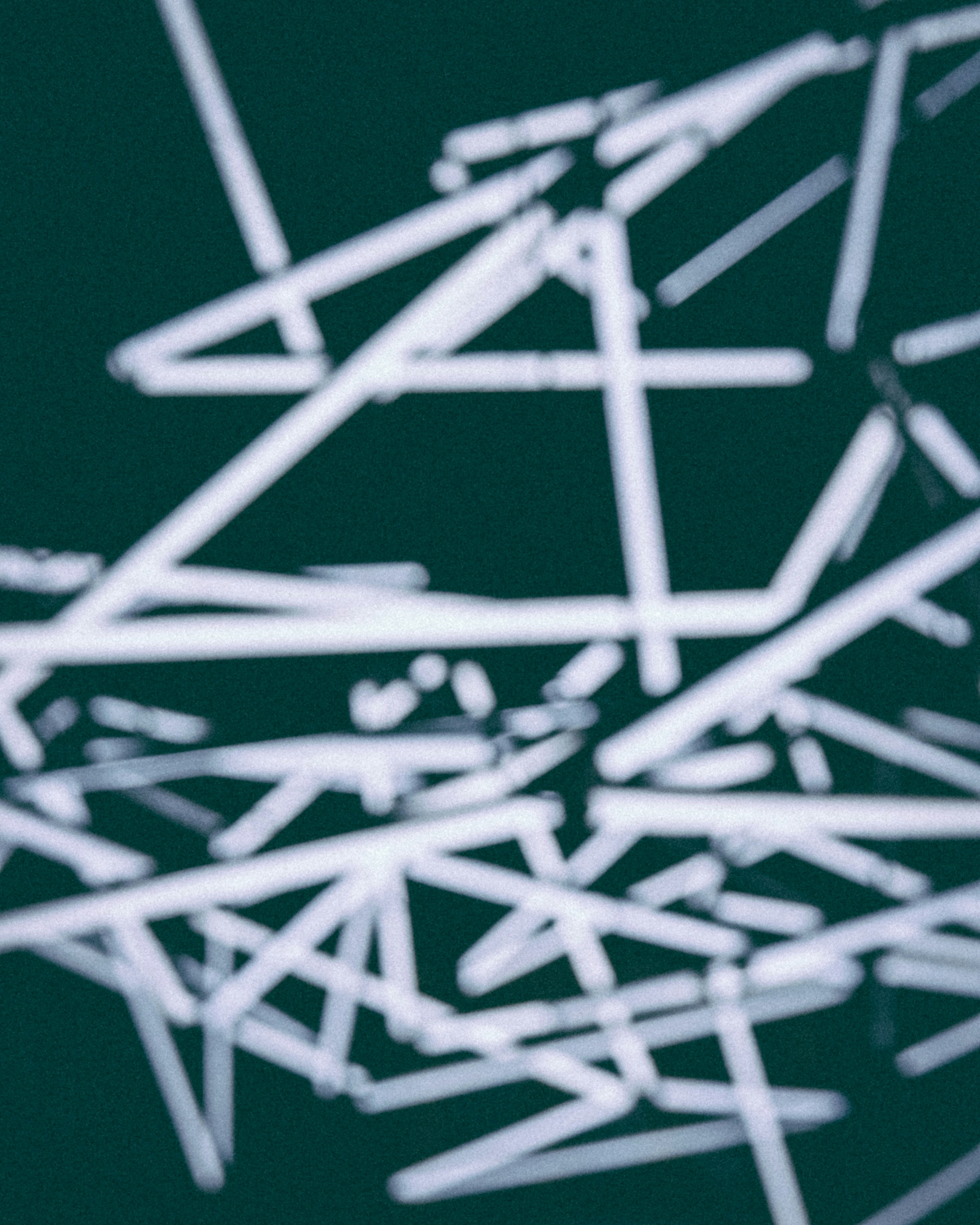 Crisscrossed white chalk lines on a teal surface create an abstract geometric pattern.