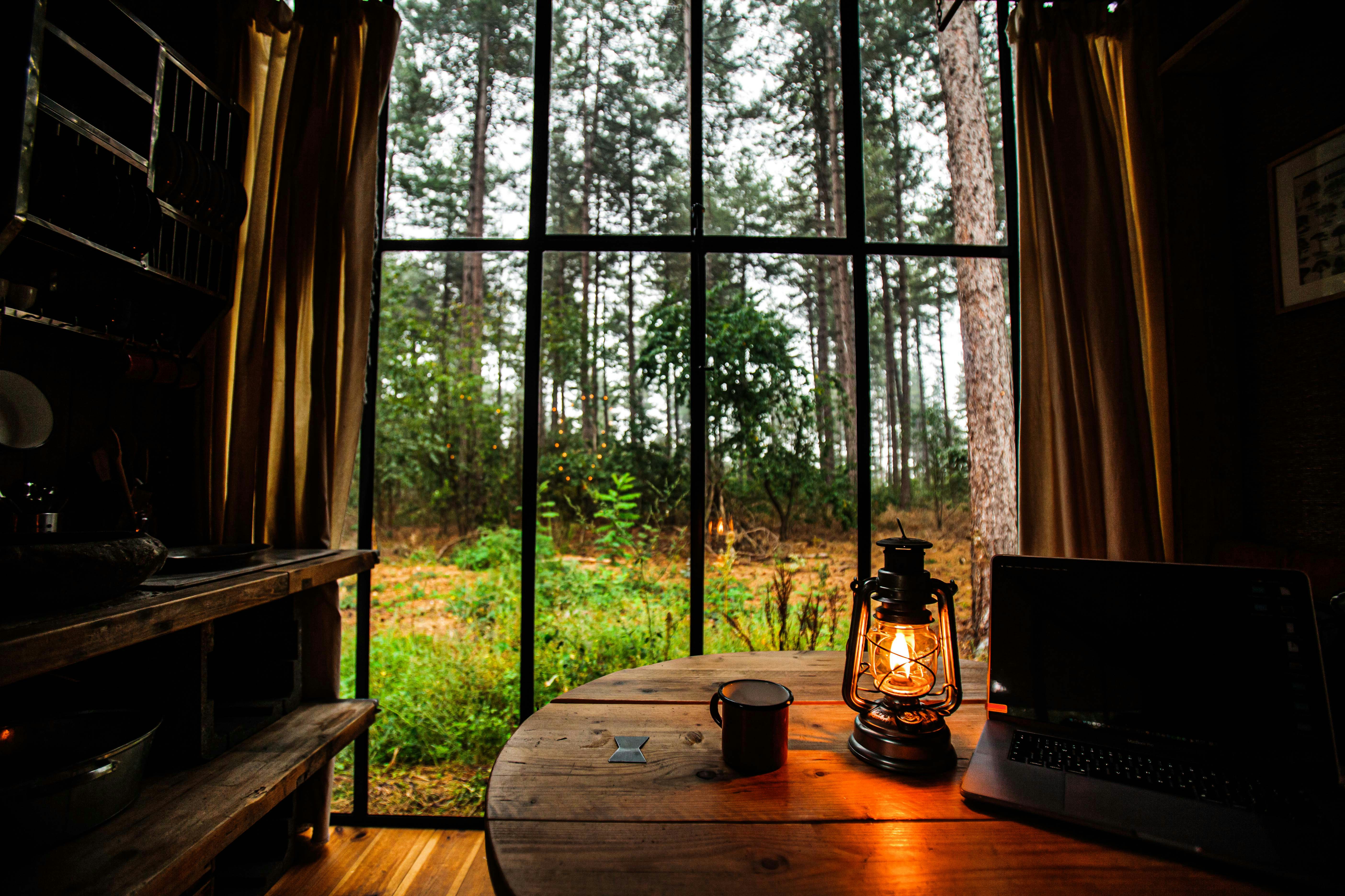Lantern Glow at a Rustic Desk Framing a Quiet Forest View