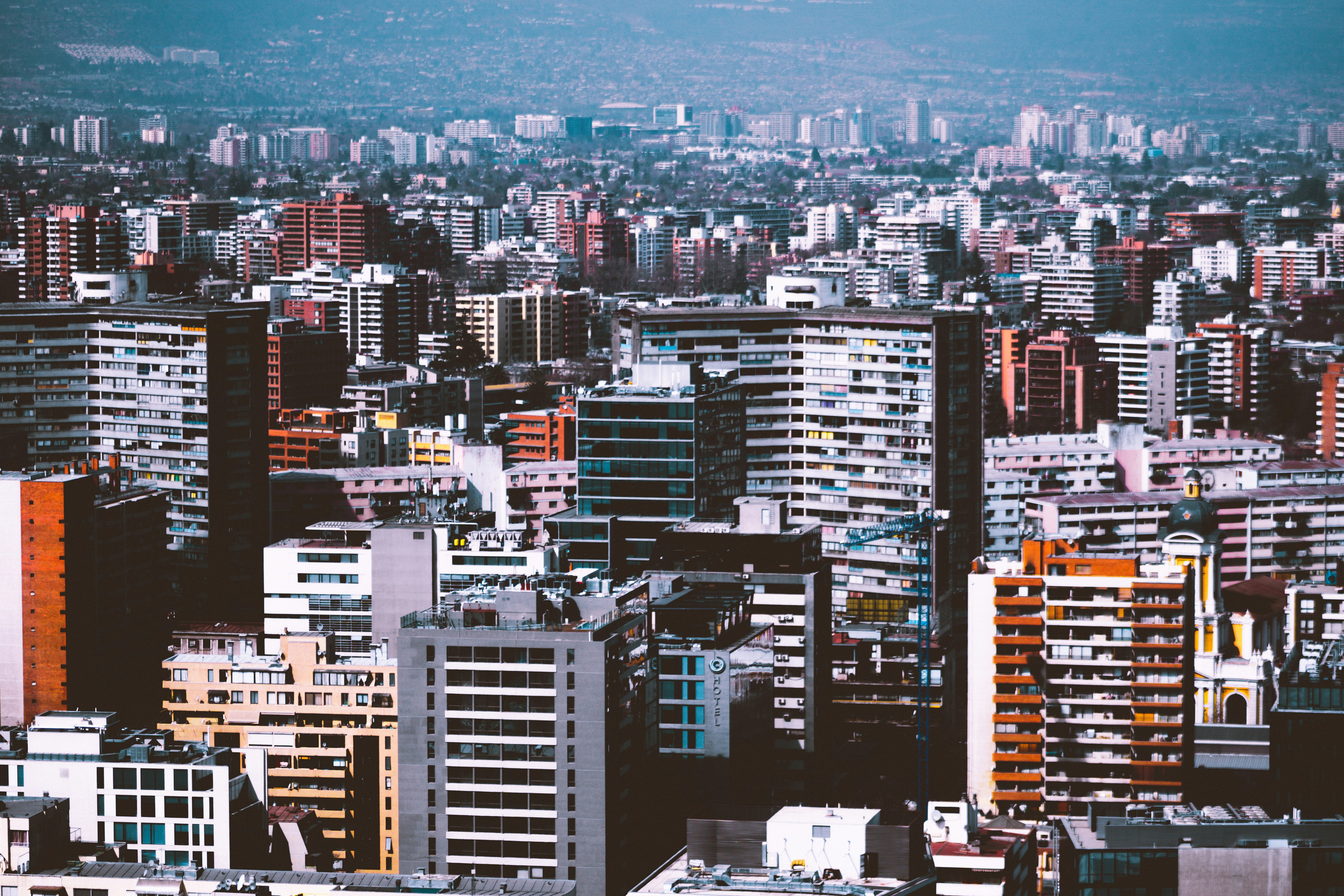 Densely packed cityscape with diverse high-rise buildings under a hazy sky.