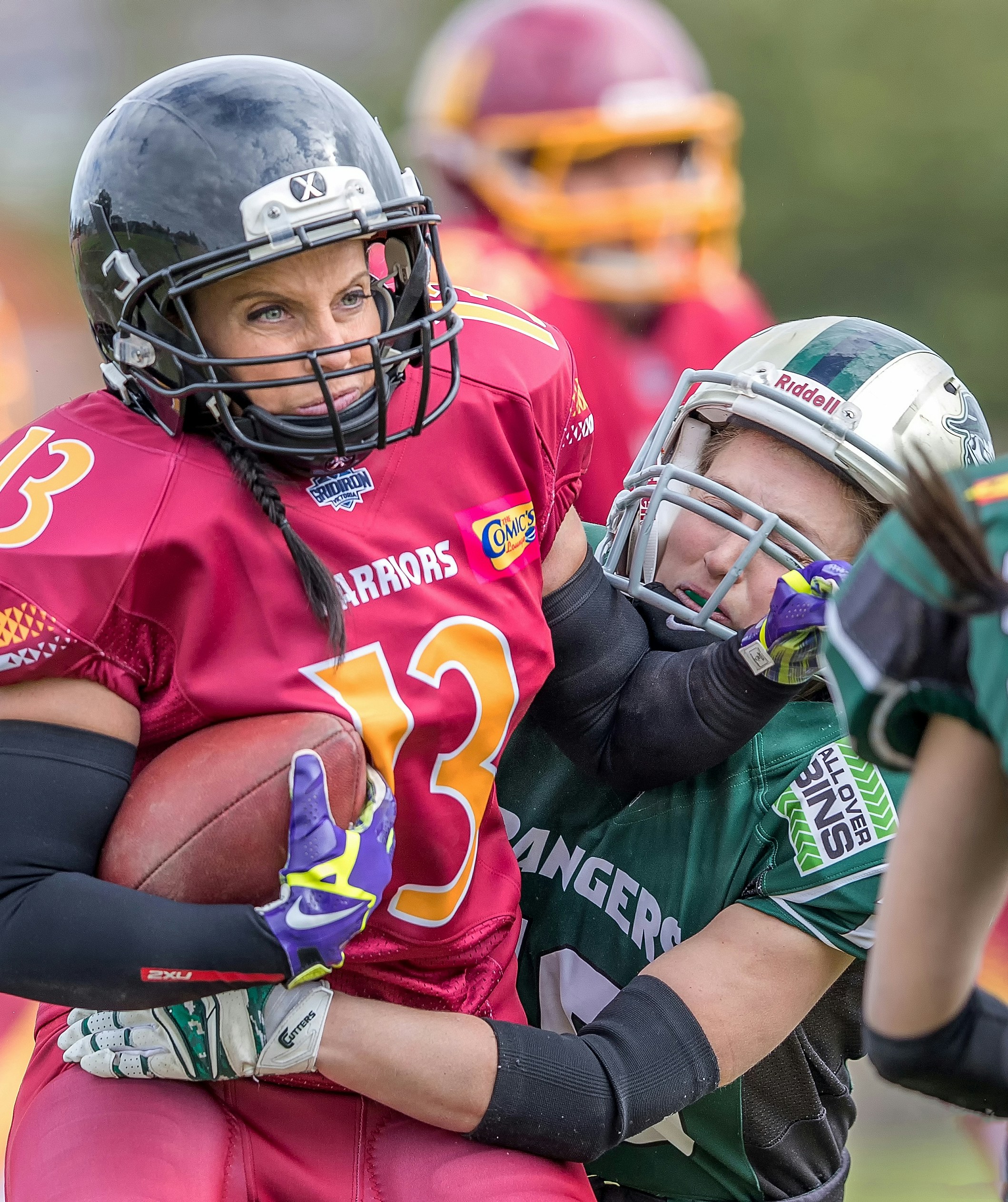 Midfield Clash: A maroon-clad ball carrier powers through a green-clad tackler